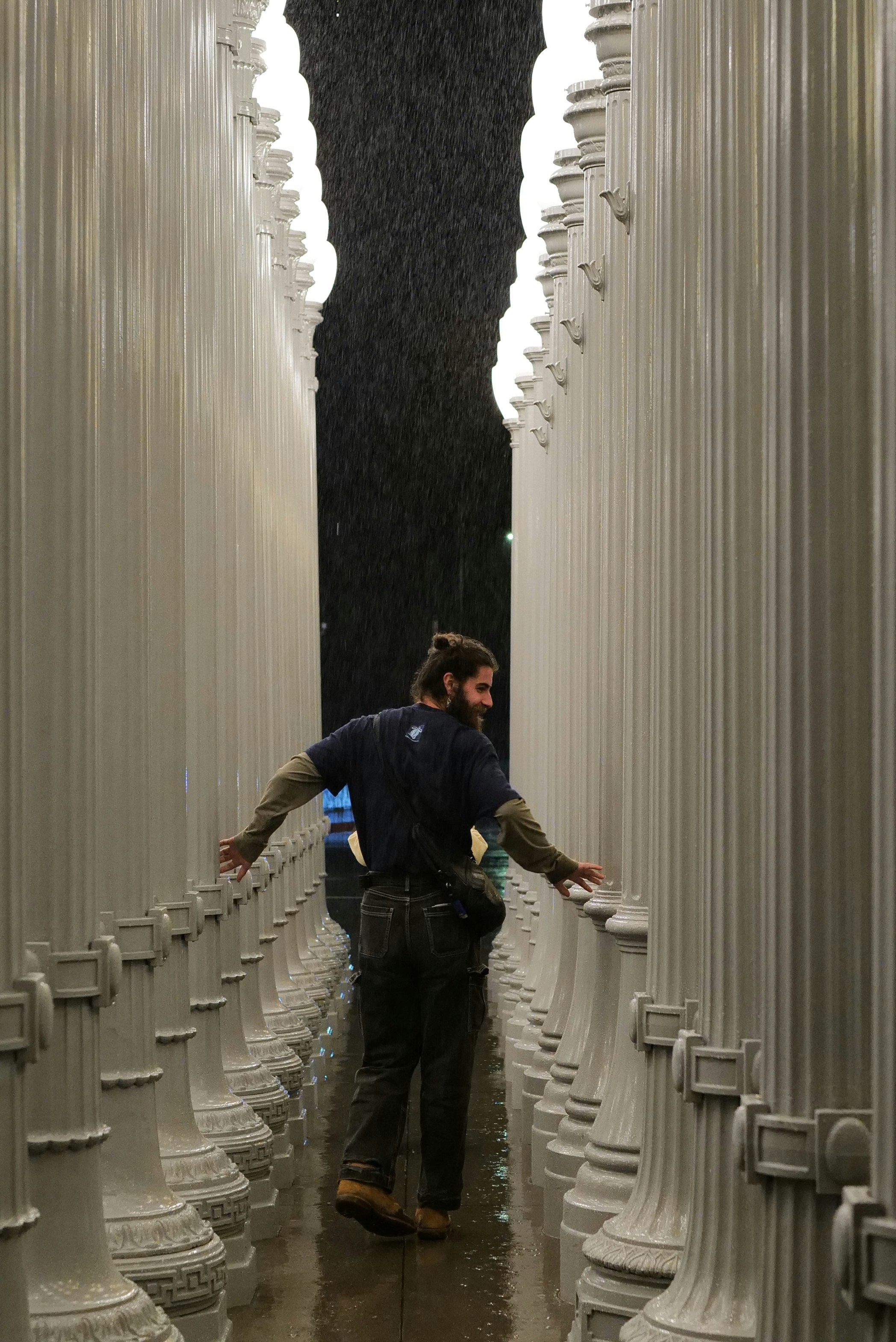 Between the Columns: A Solitary Wanderer in the Luminous Corridor