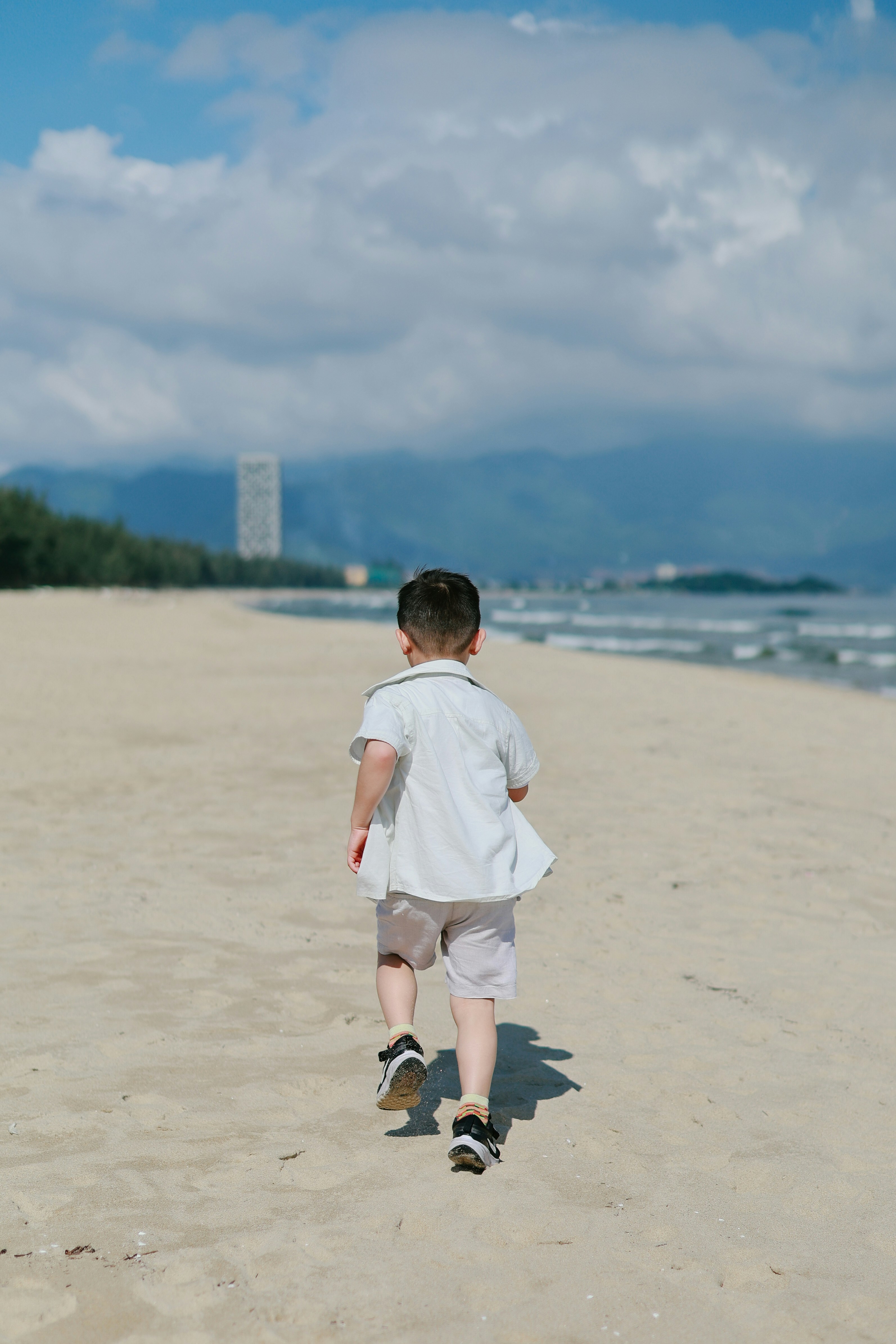 Child on a sunlit shoreline chasing the horizon