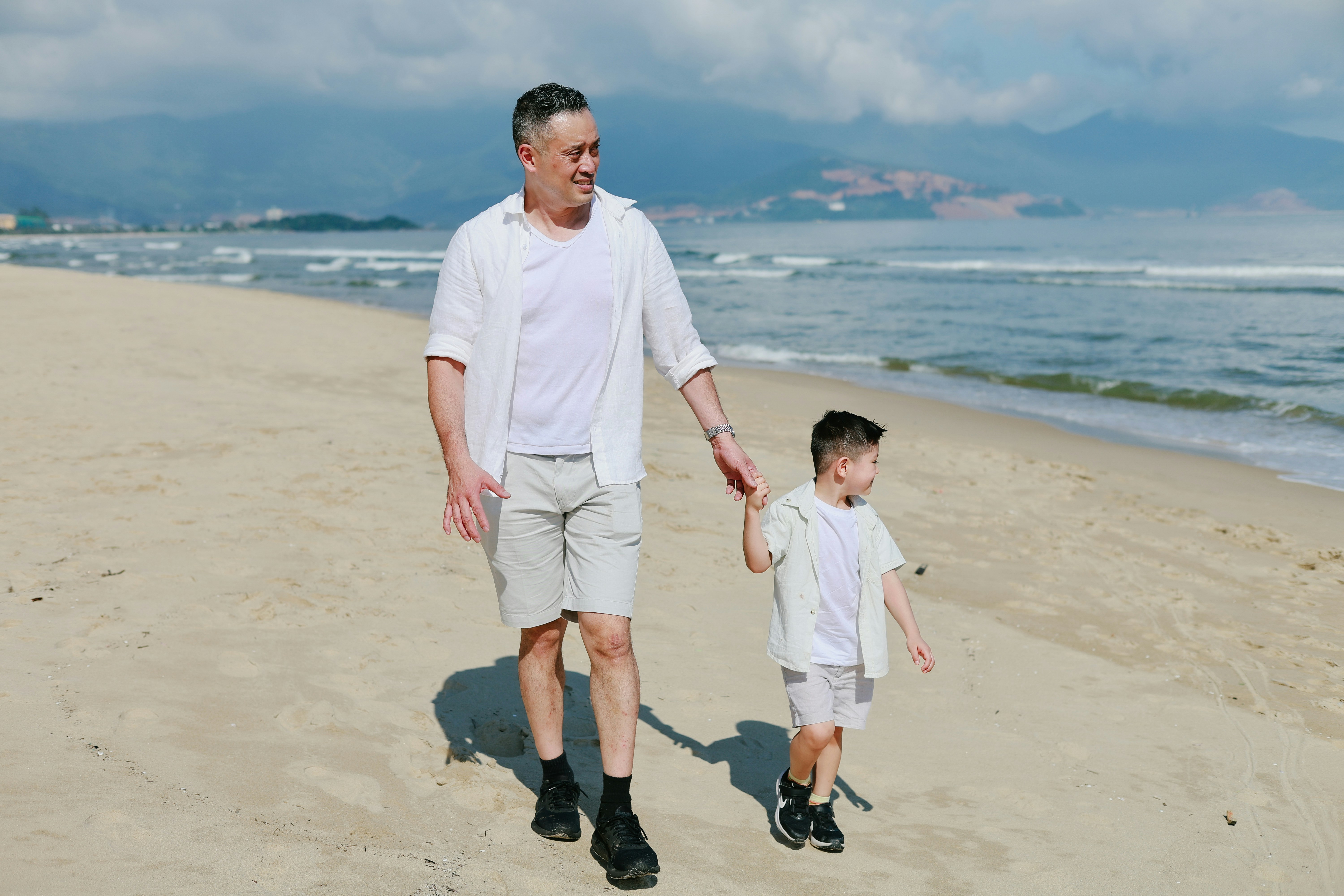 Father and Son Stroll the Sunlit Coast