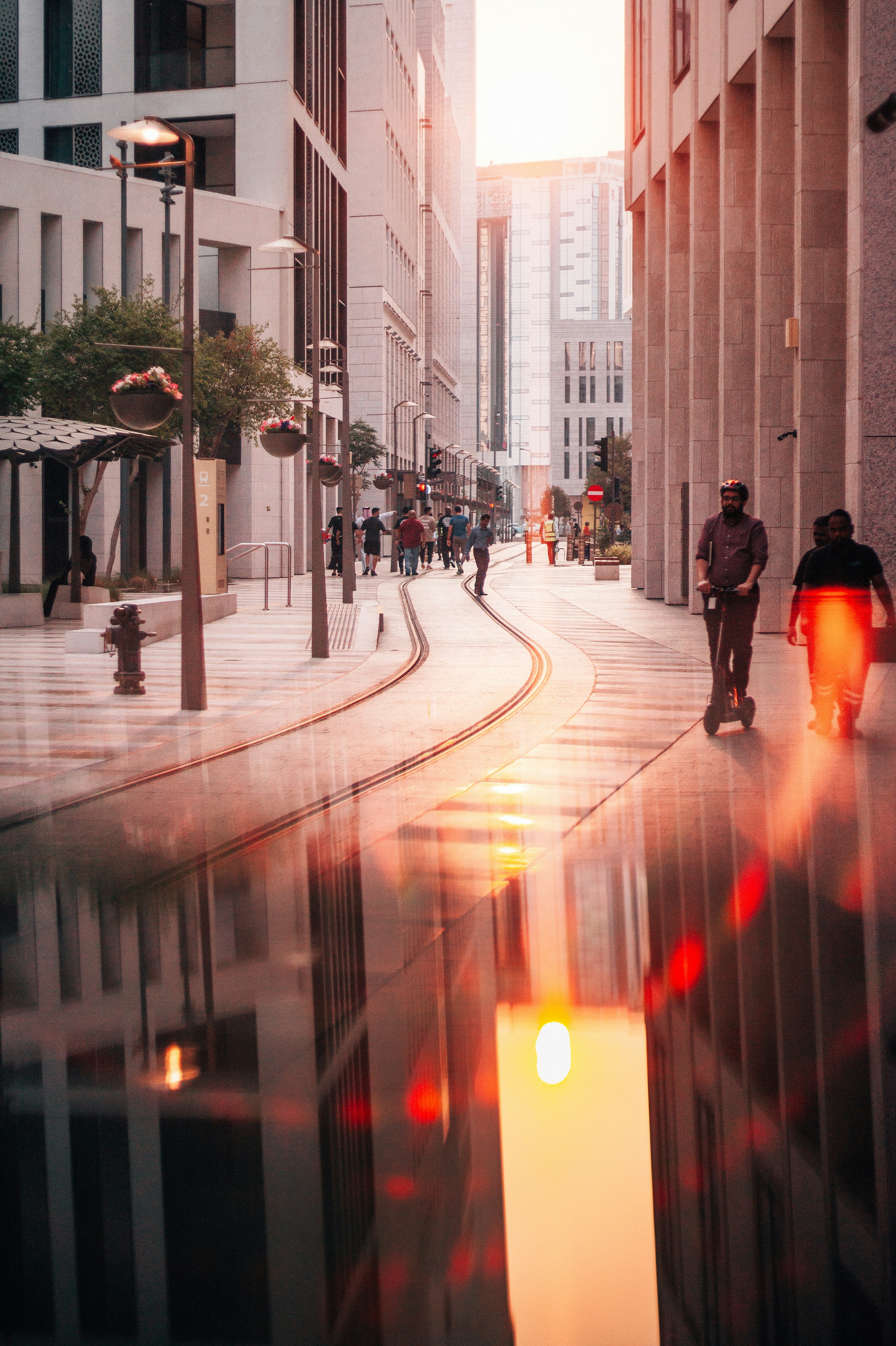 Sunlit Transit: A City Street Framed by Reflections and Pedestrians