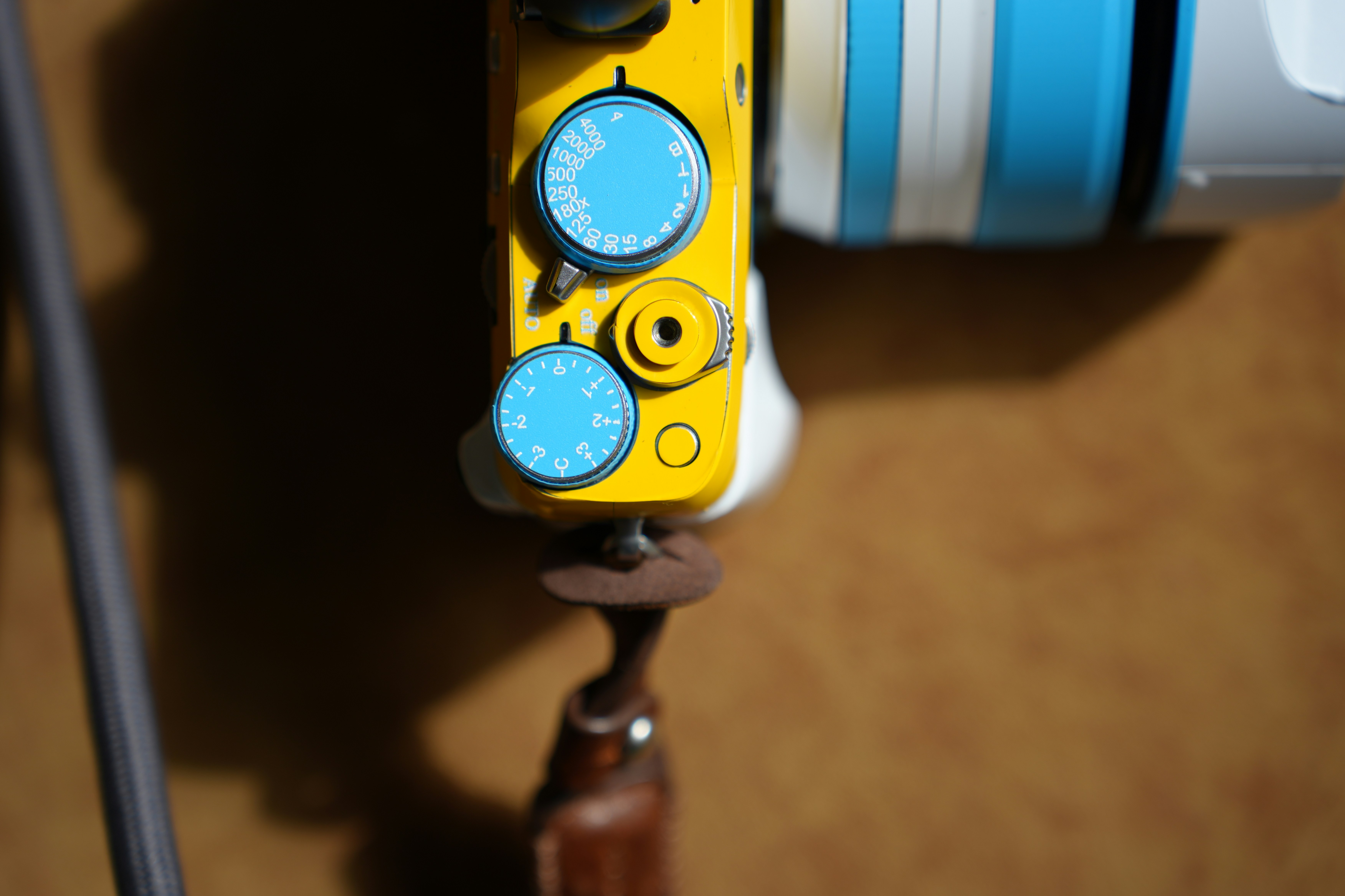 Close-up of yellow camera with blue dials and strap