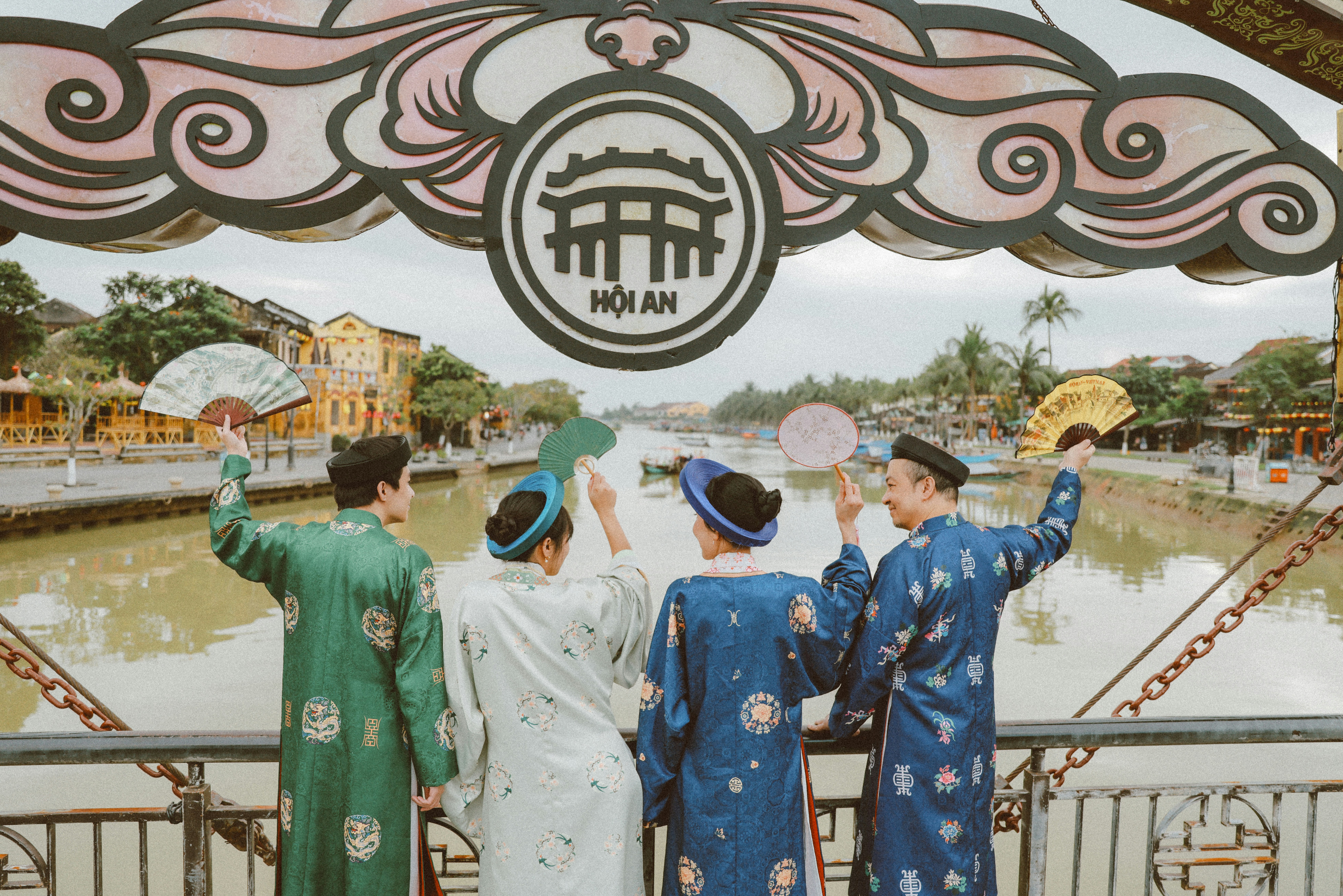 Four people in traditional clothing holding fans