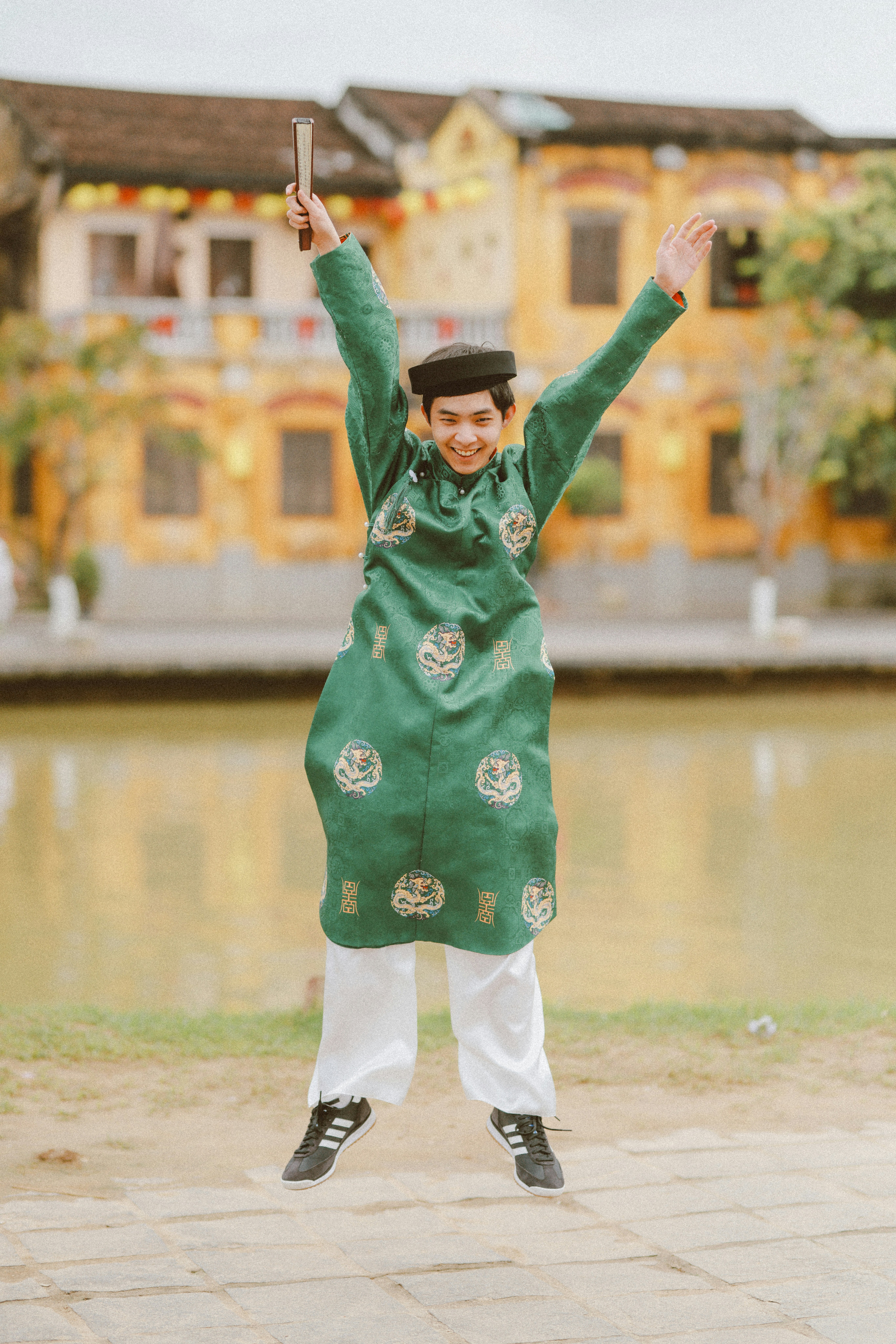 Joyful leap in a sunlit courtyard in traditional green áo dài