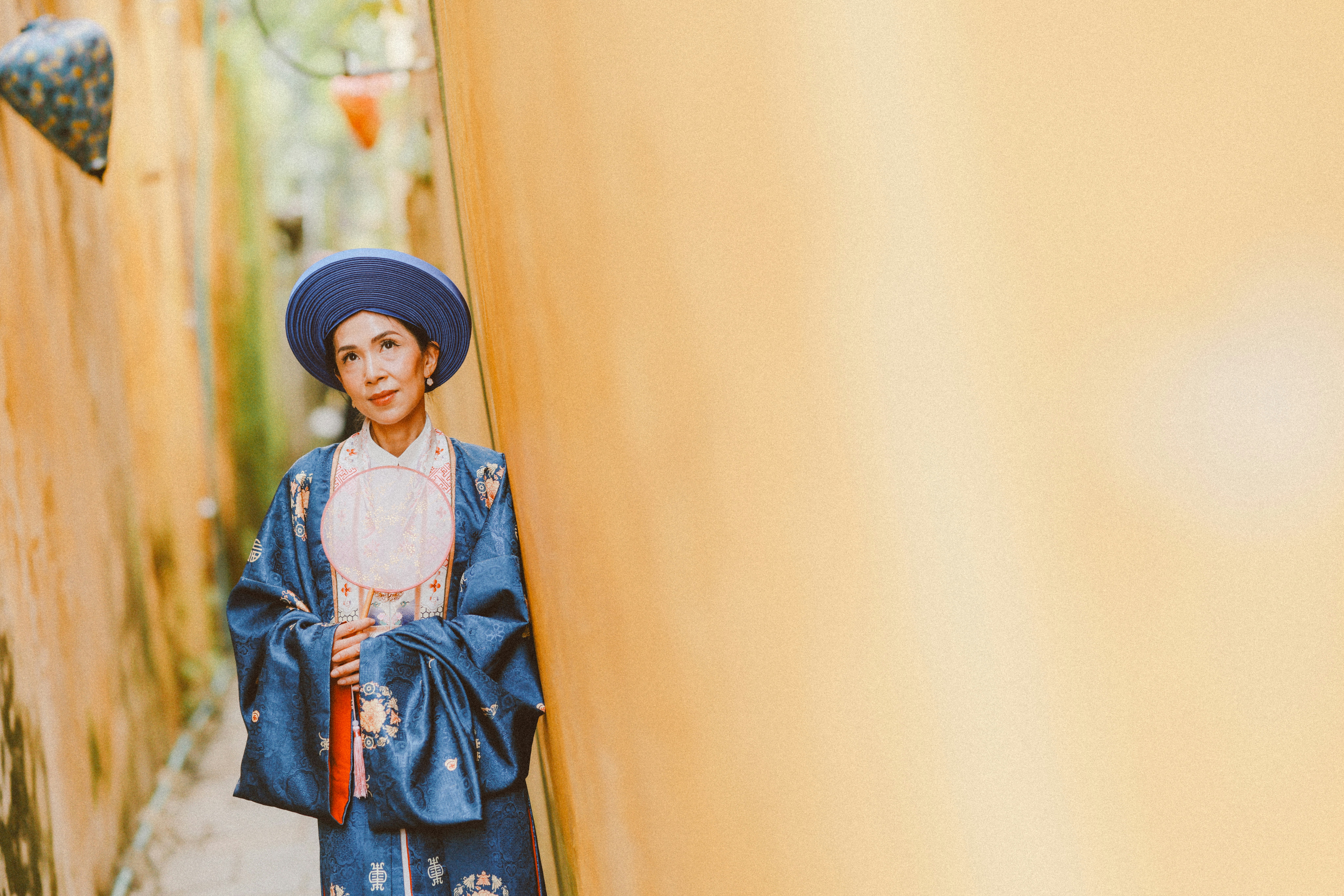 Portrait in a Narrow Alley: Traditional Attire Against a Sunlit Wall