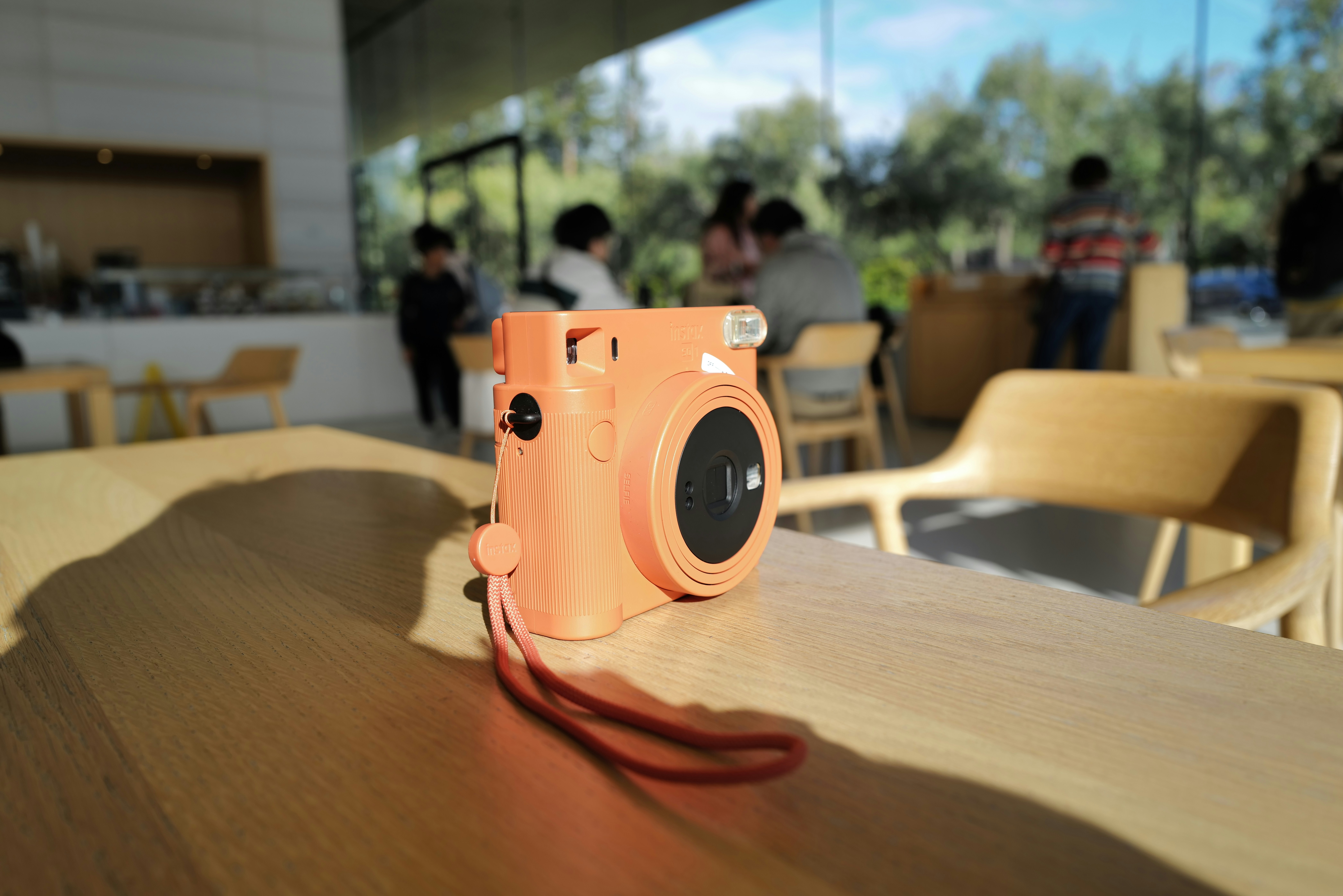 Peachy Compact: A coral camera rests on a sunlit cafe table