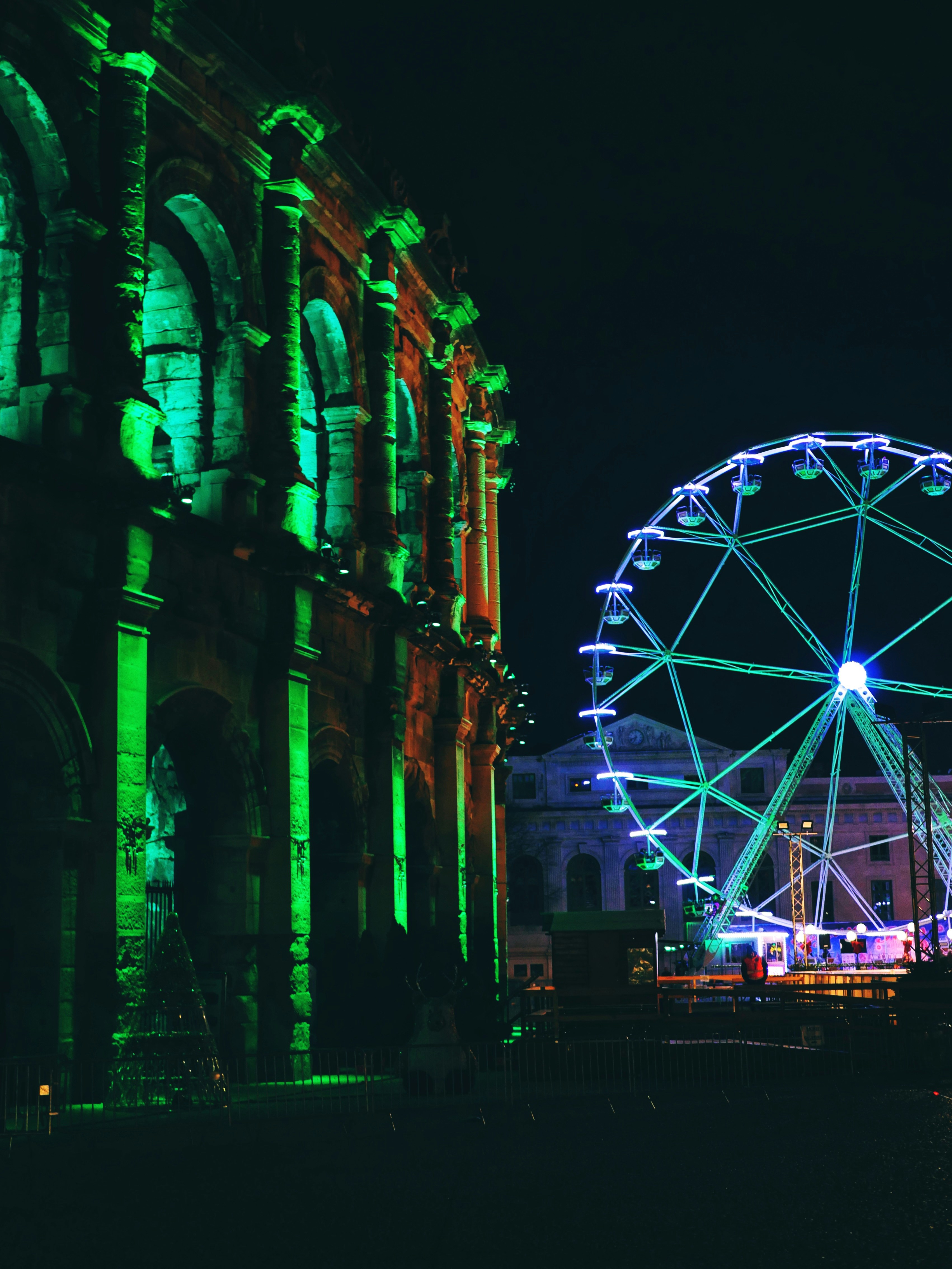 Neon Colosseum at Night: Green Arches Meet a Blue Wheel