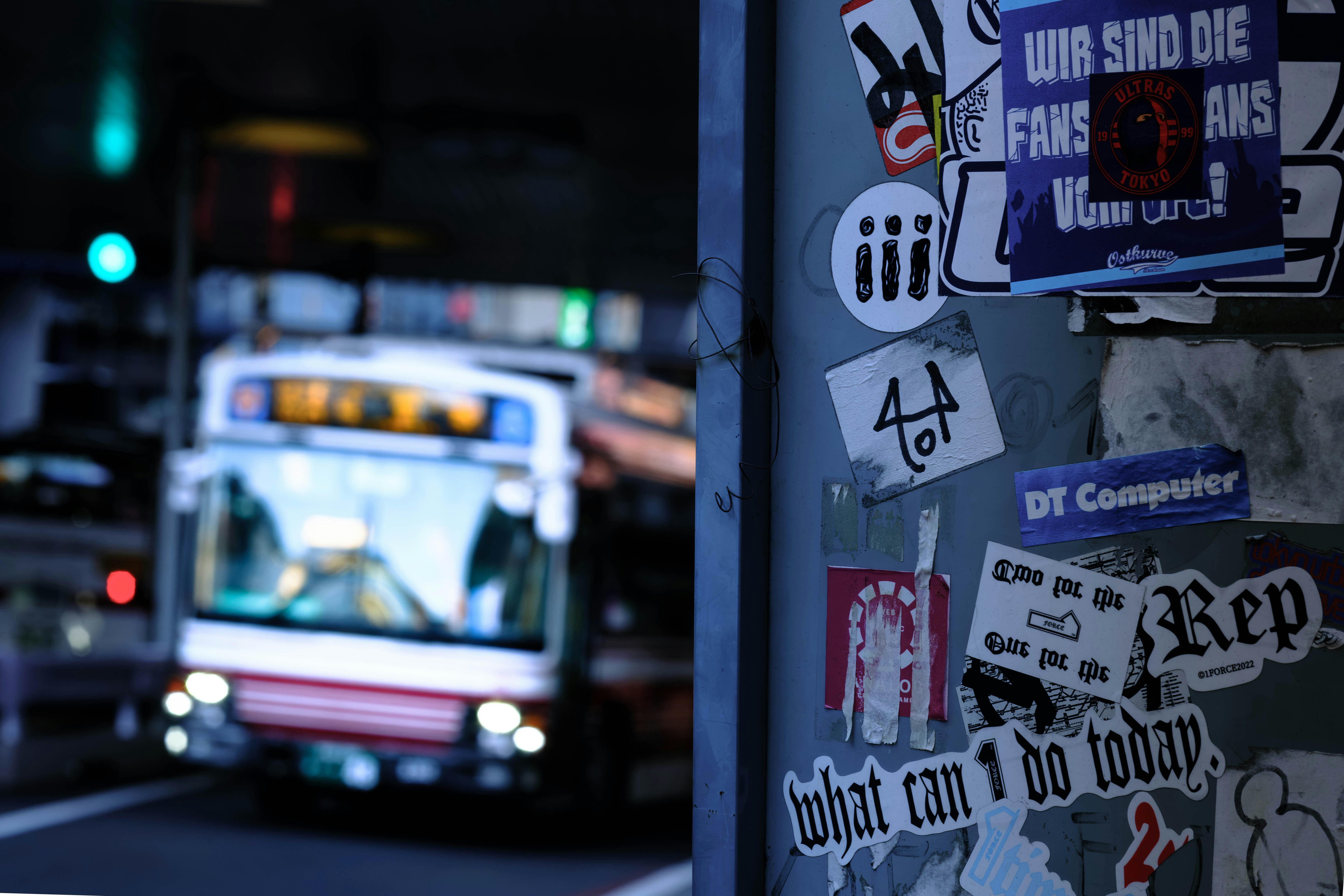 Stickered lamppost in a blurred city corridor