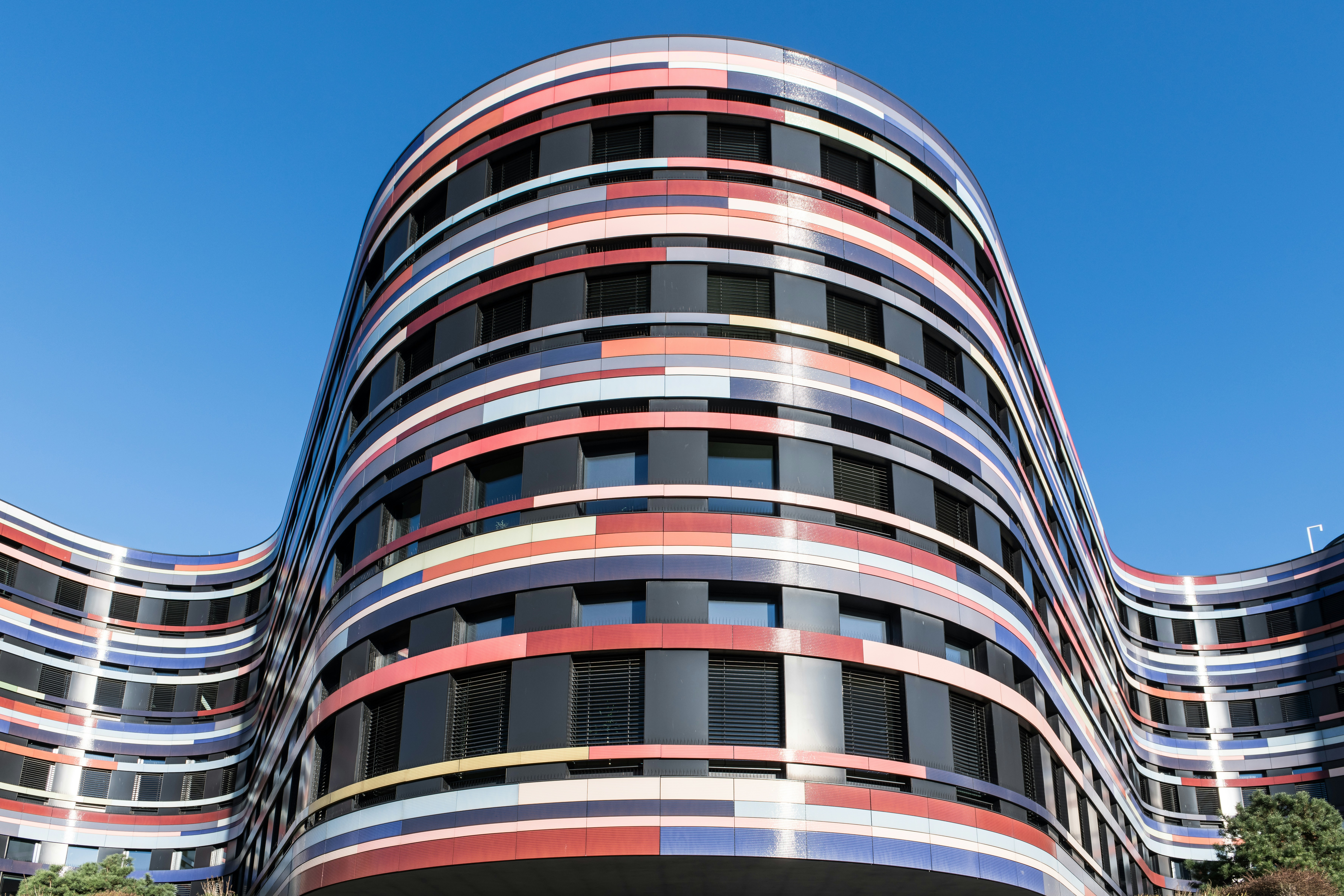 Curved Ribbon Facade: Neon Stripes on a Modernist Capsule