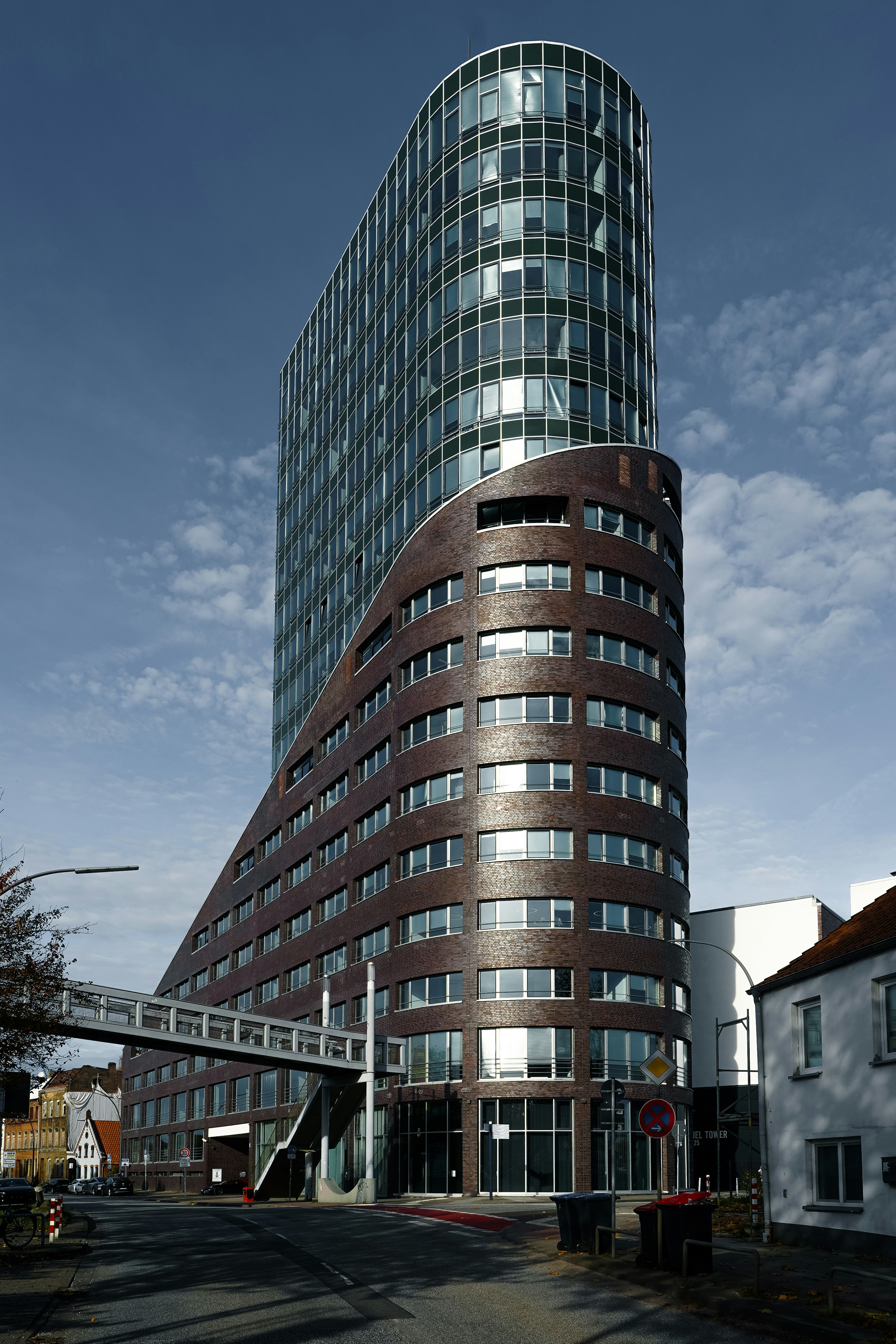 Curved Glass Facade Rises: A Modern High-Rire Center Against a Sky of Soft Clouds