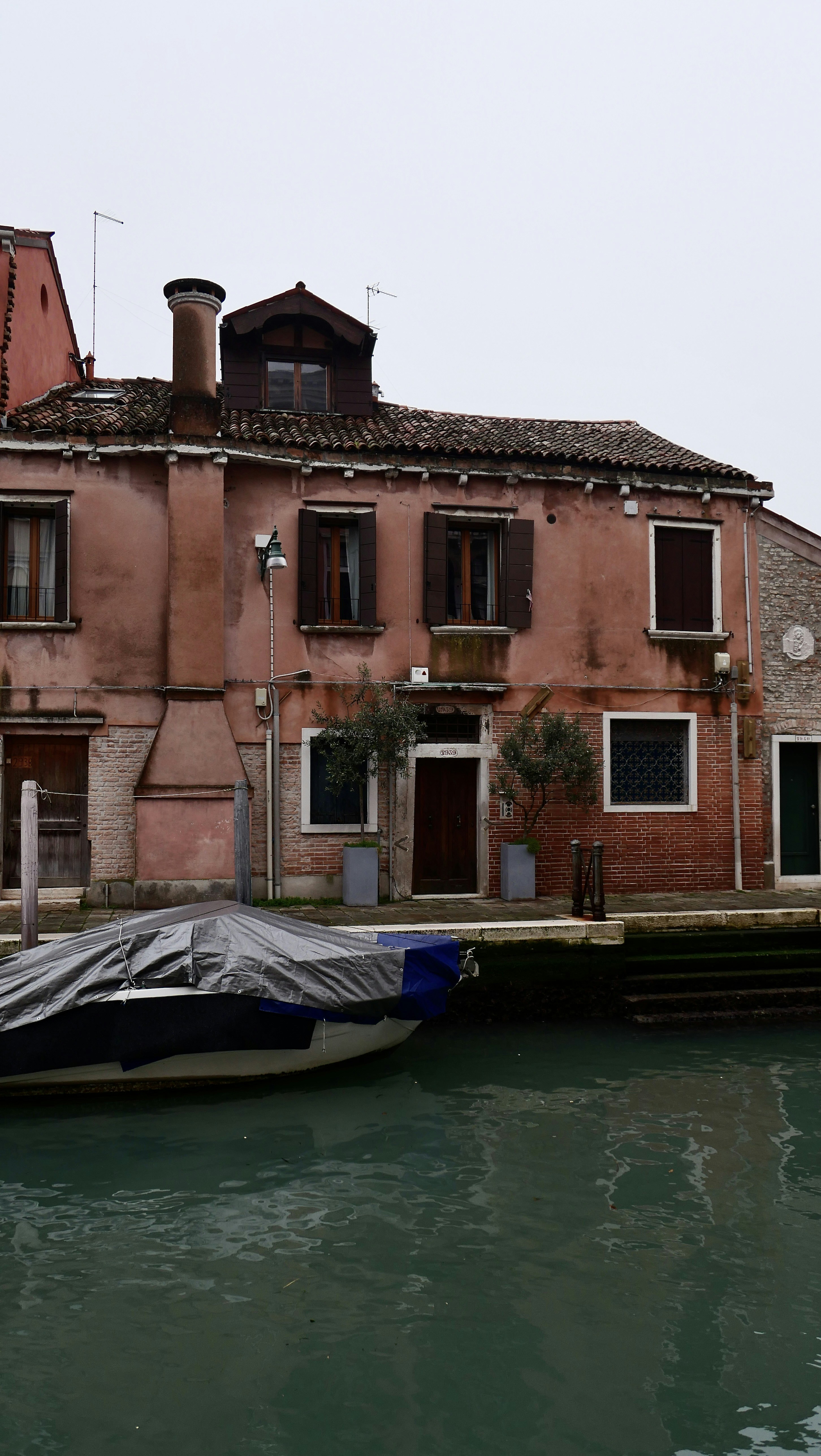 Riverside Facade: Weathered Pink House Overlooking a Quiet Canal