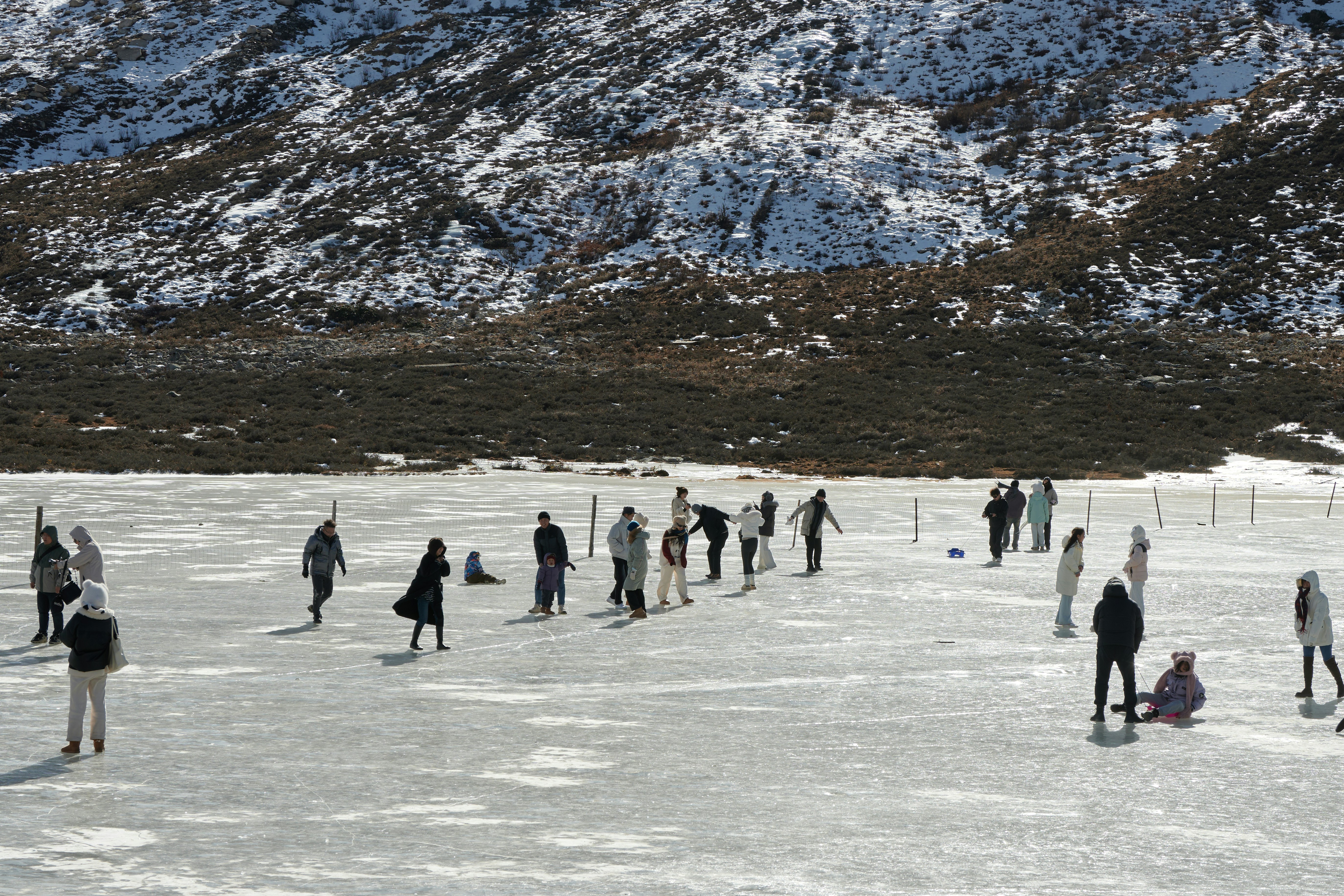 Lines of Visitors Across a Snowy Plain Beneath Grayed Peaks