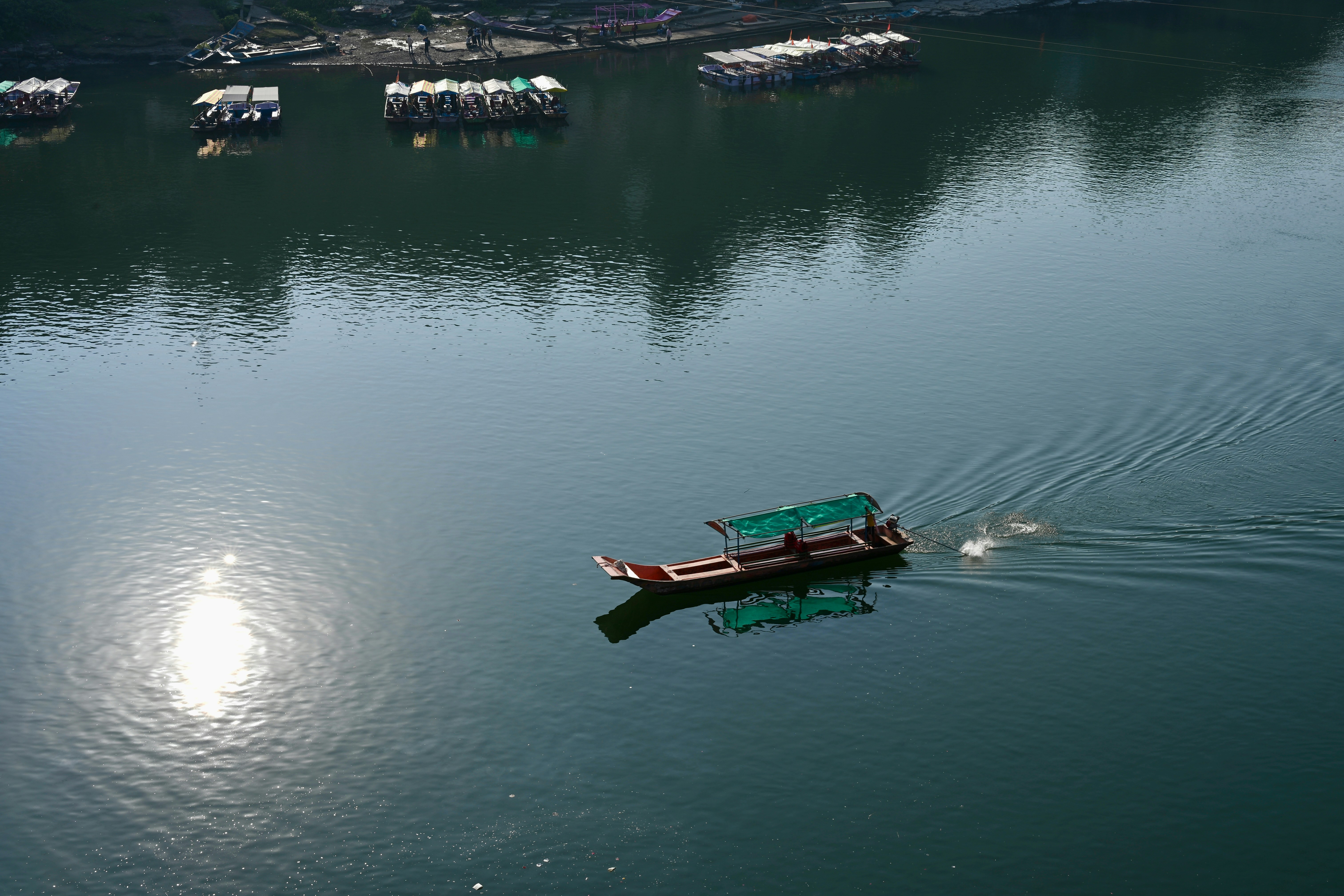Green-hooded Boat Gliding Across A Mirror-like Water