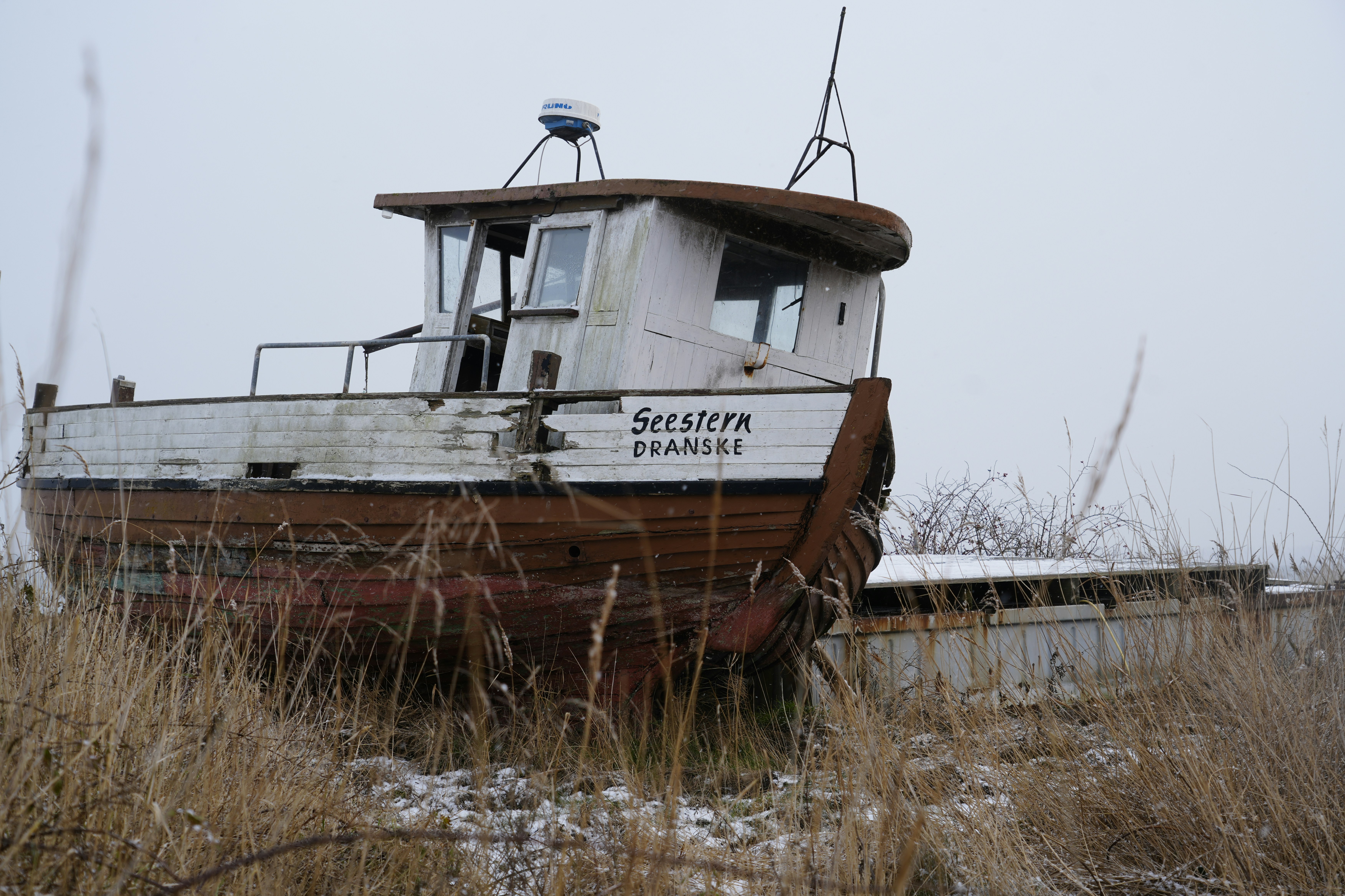 Relic of the Quiet Channel: An Abandoned Boat in Winter Grasses