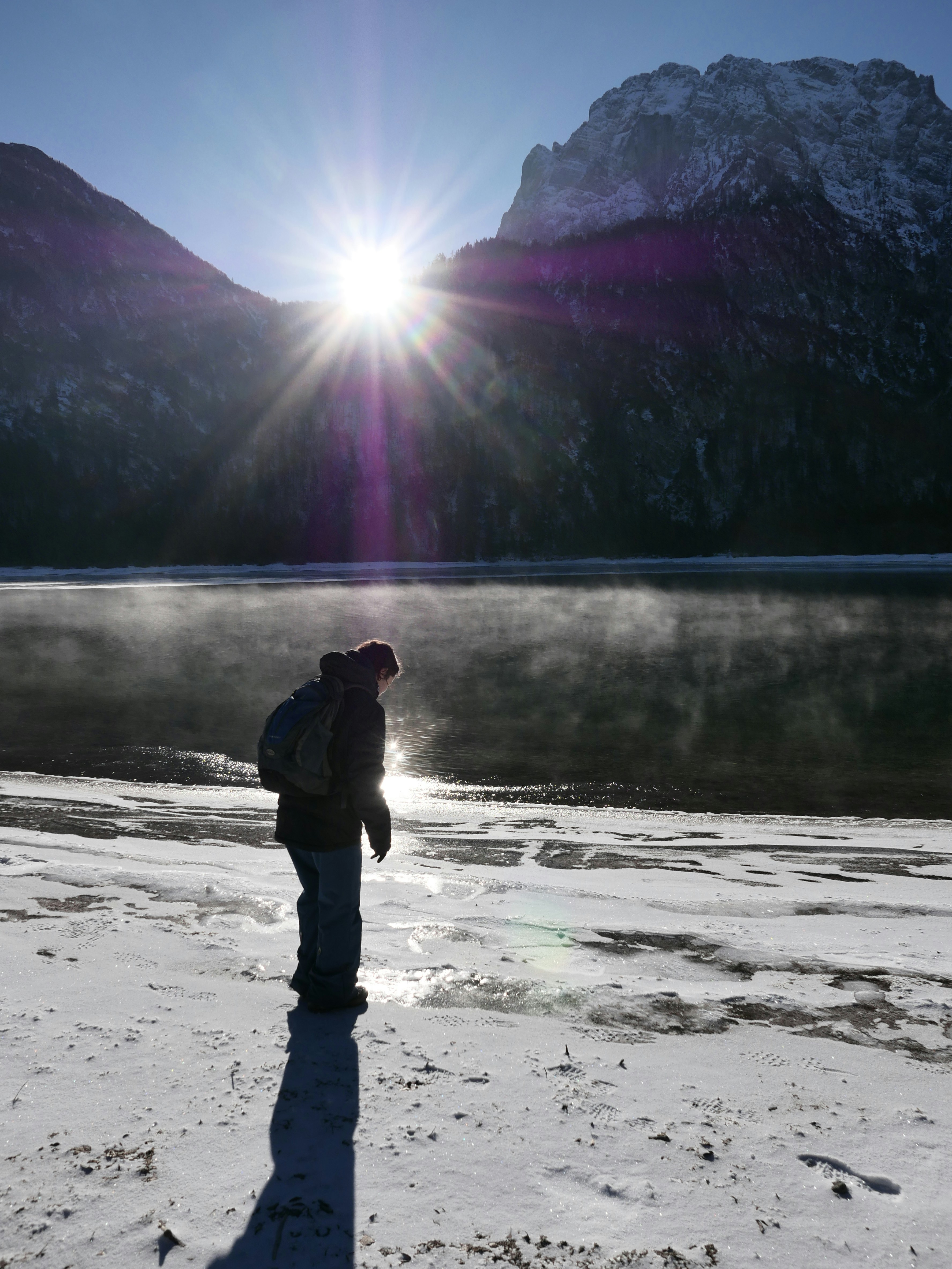 Sunburst Over Frozen Shore: A Lone Hiker Anchored by Shadow