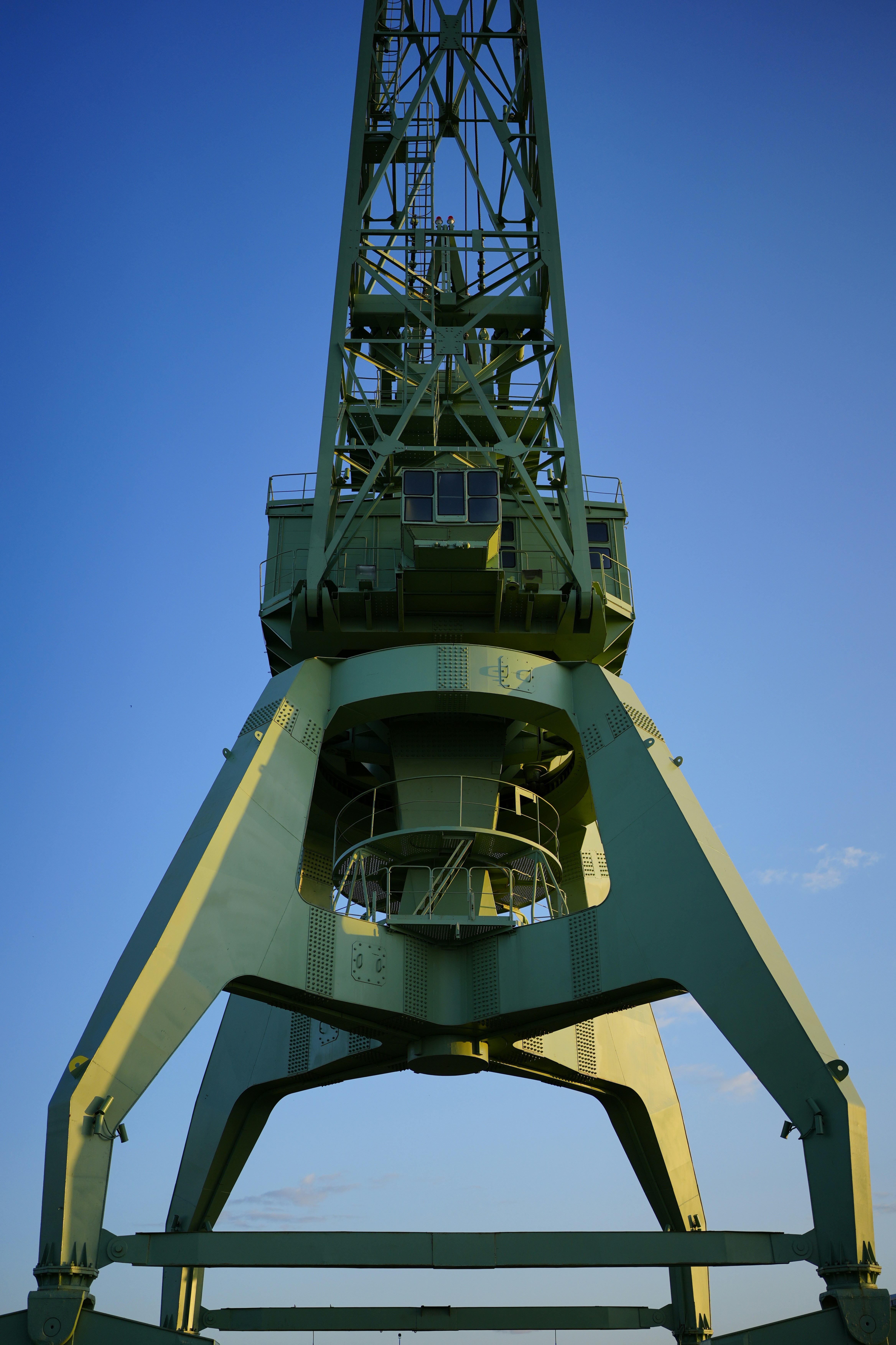 Green Crane Structure Reaching into a Clear Blue Sky
