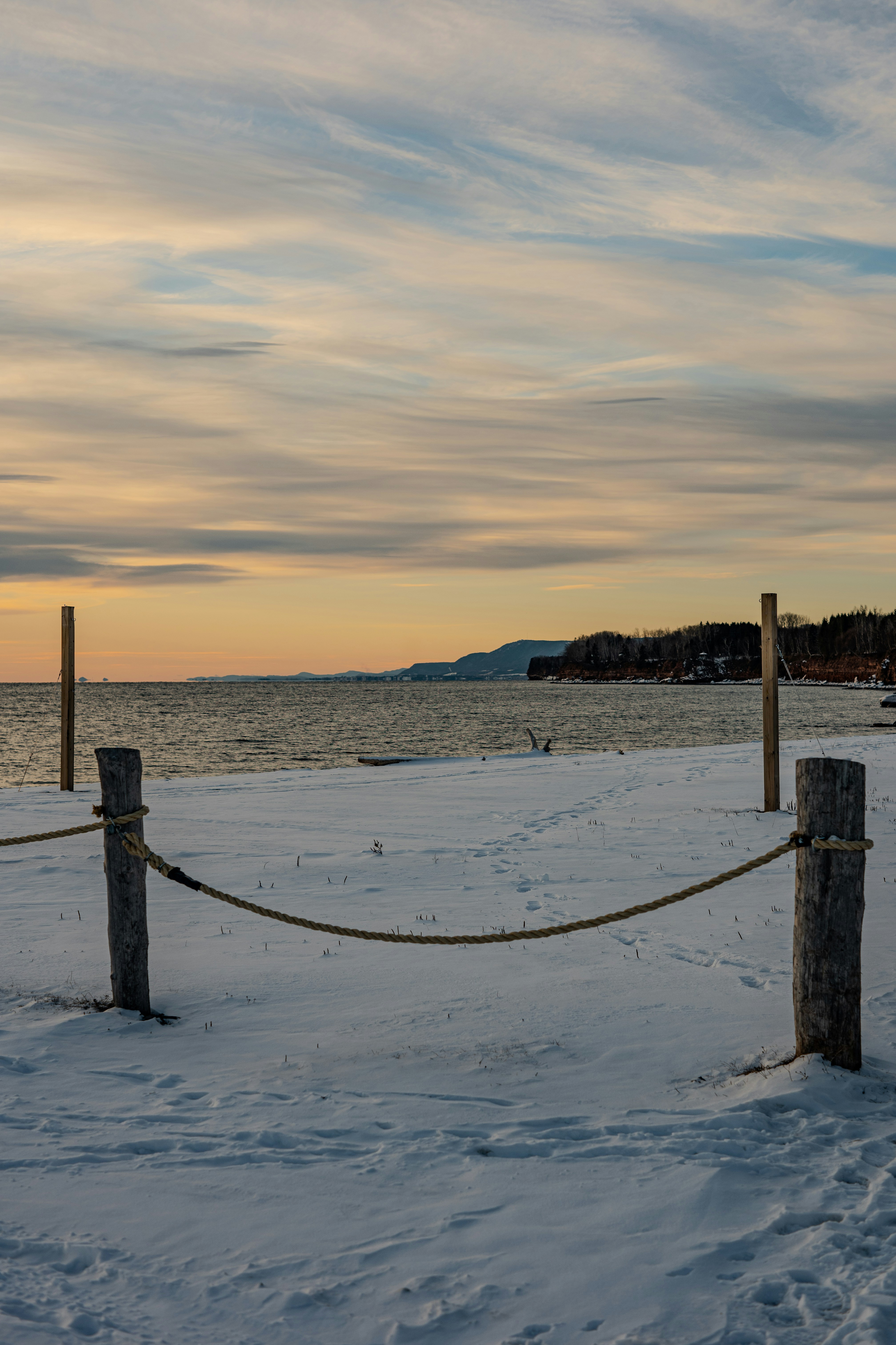 Snowbound Pier: Rope Fence Framing a Distant Sunset