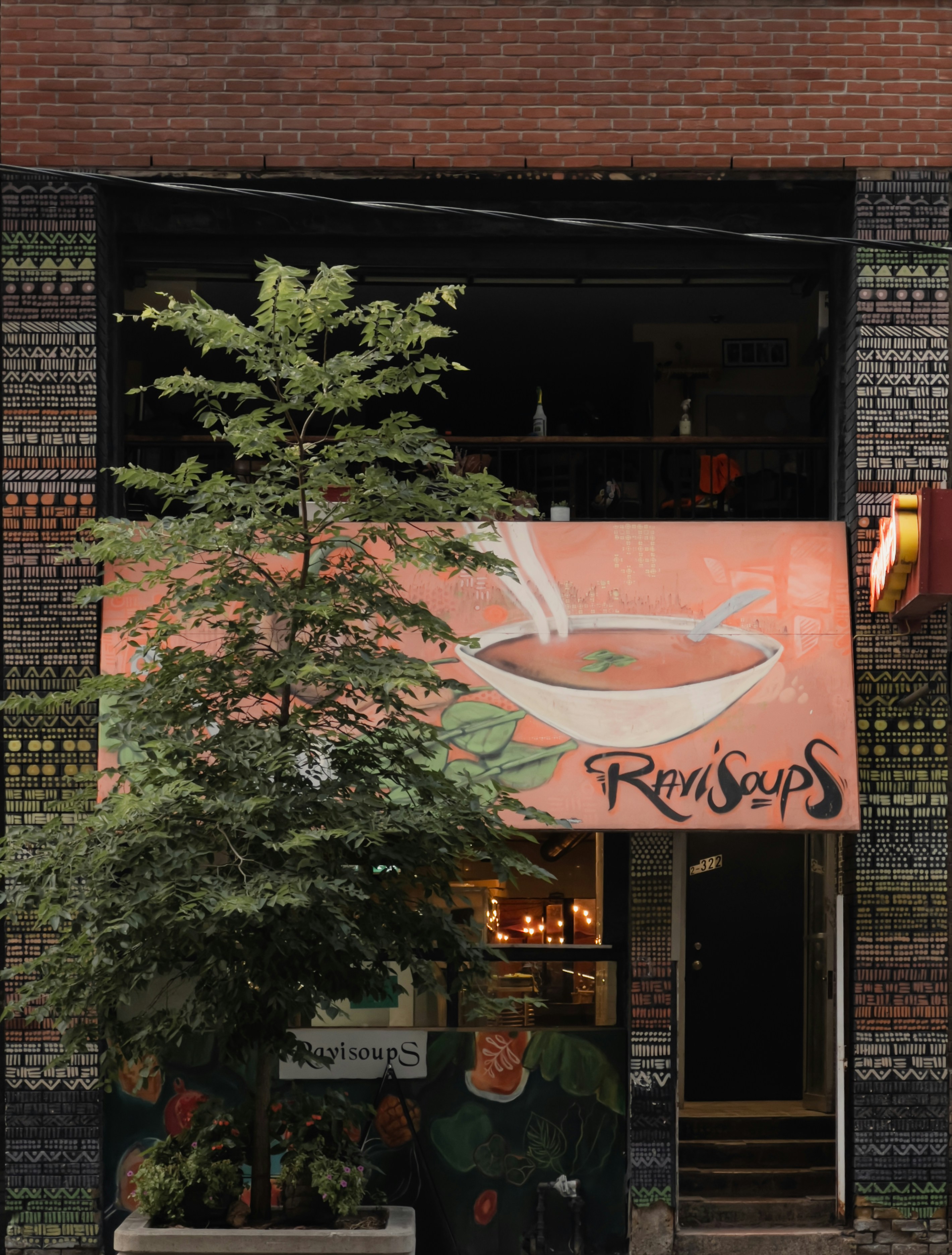Cafe Signage Emerges Behind a Tree in an Urban Brick Façade