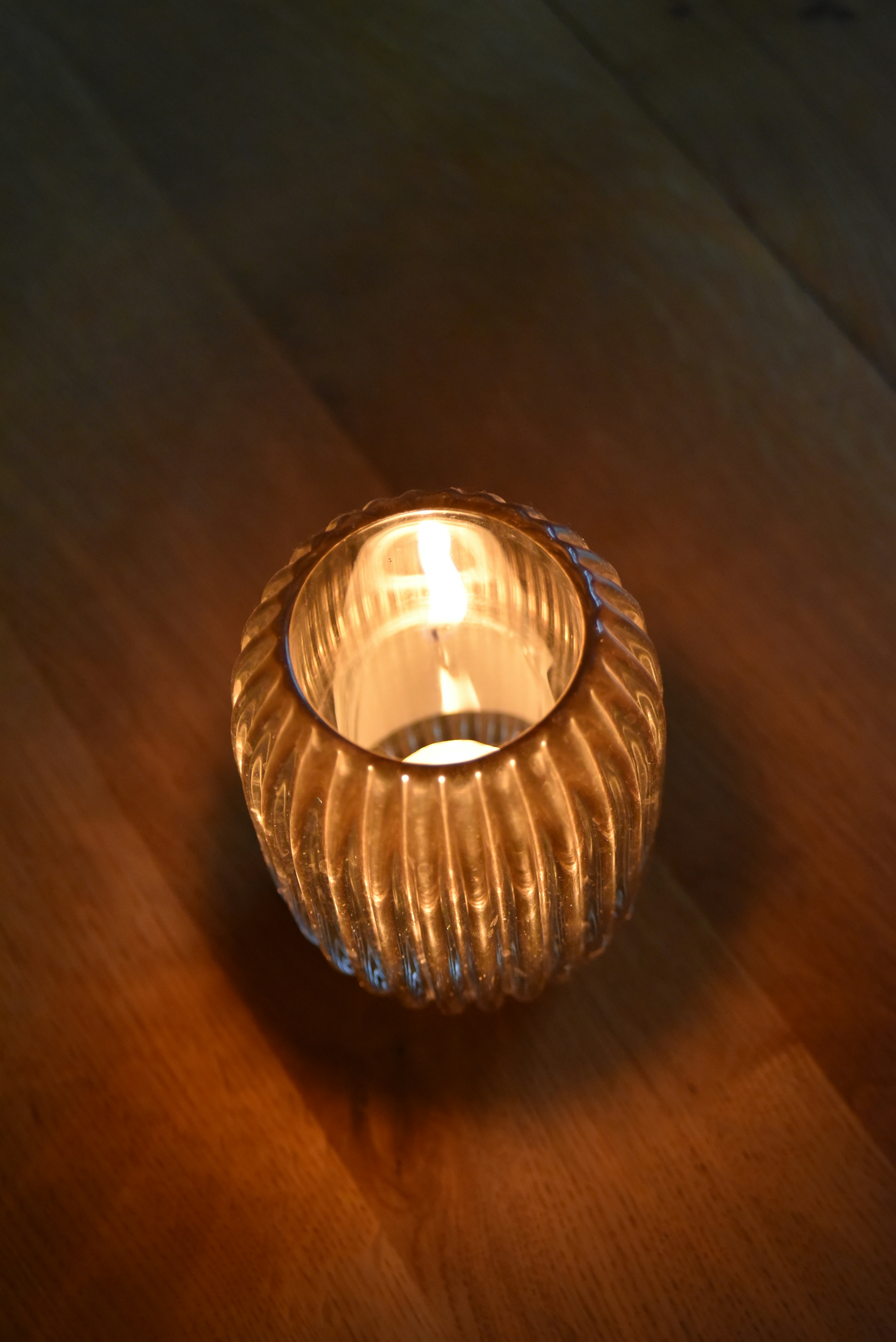 Amber Flame in a Glass Vessel: A Quiet Glow on Wood Grain