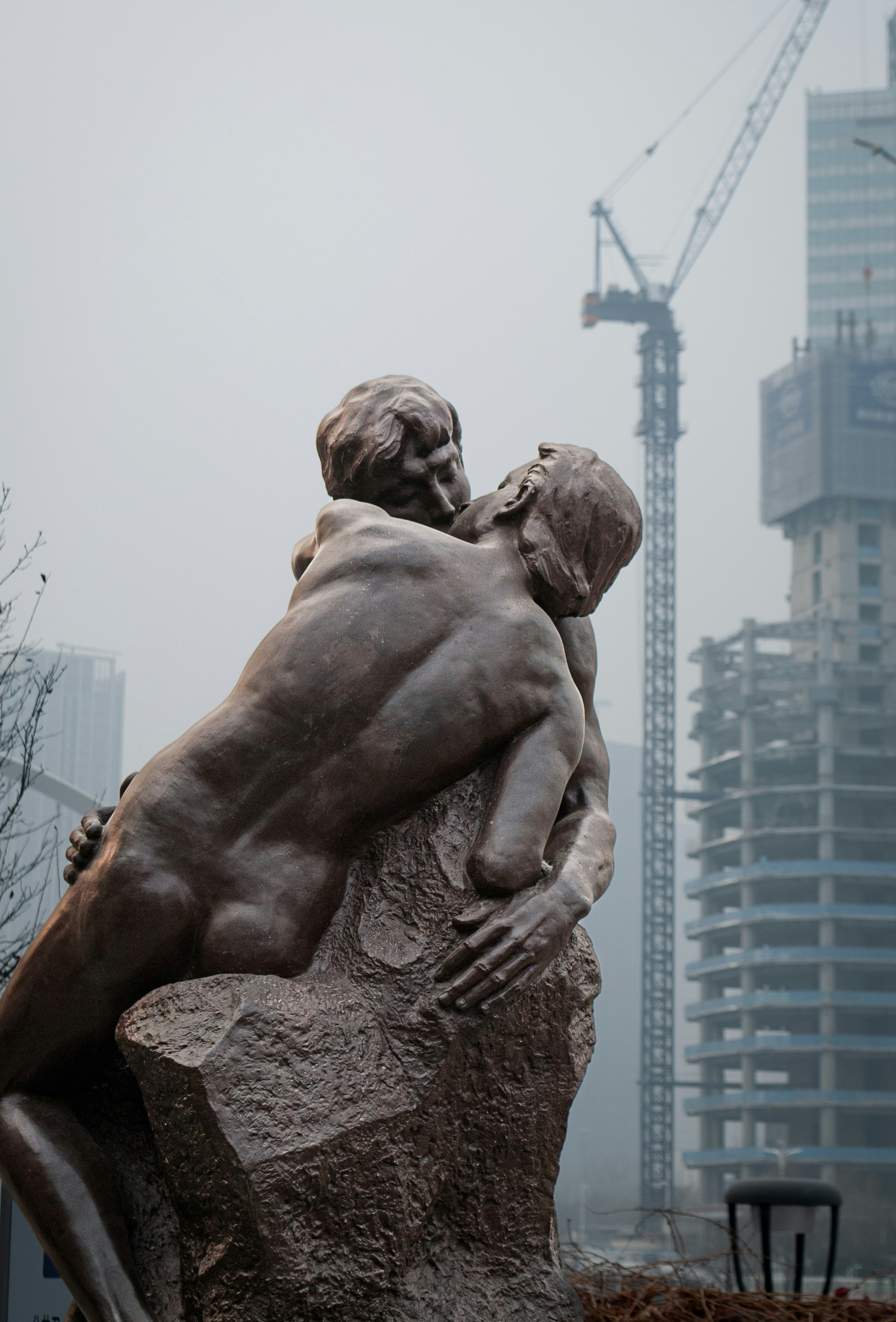 Concrete embrace: a bronze sculpture against a city of cranes