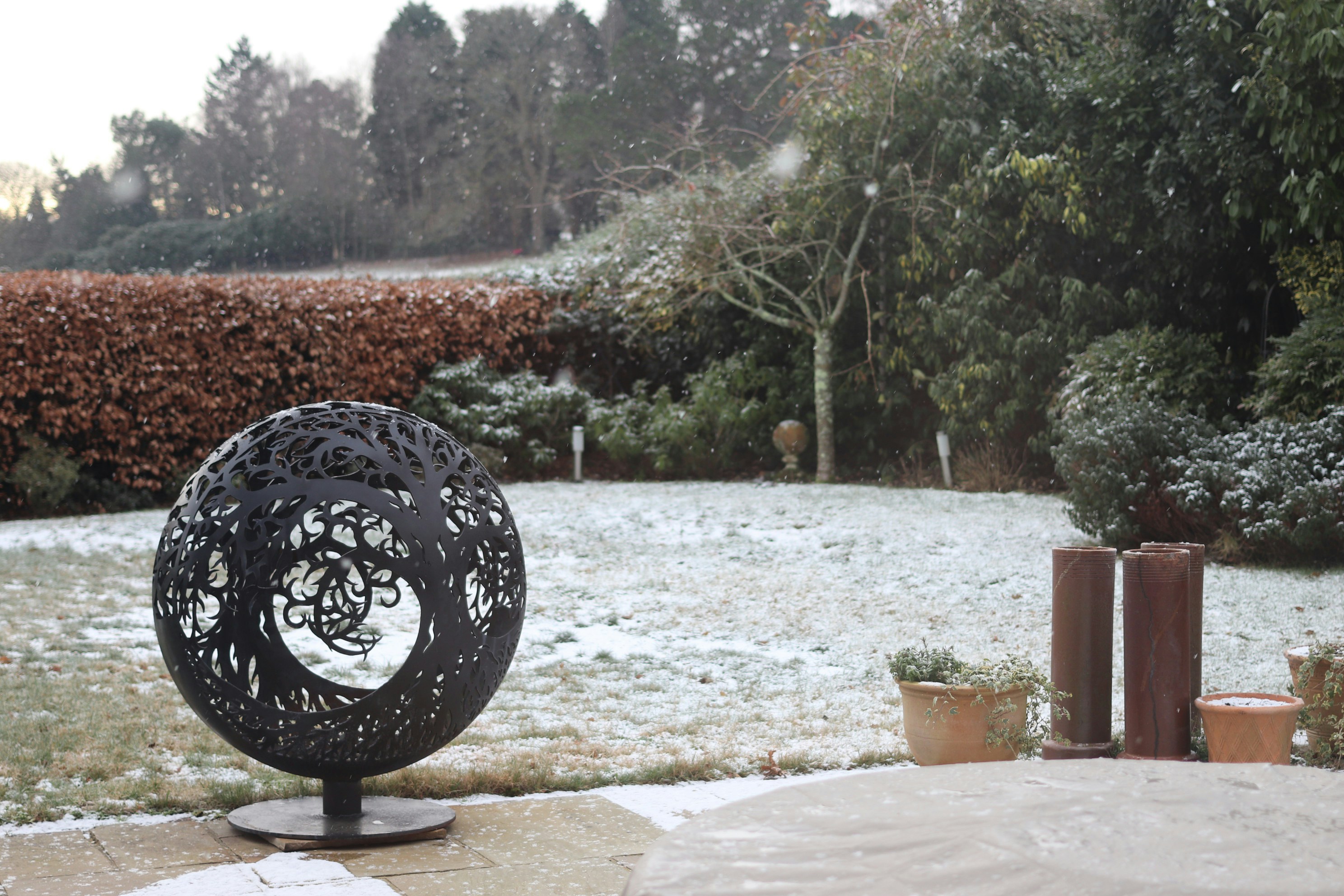 Ornamental sphere contrasts with frosted garden backdrop