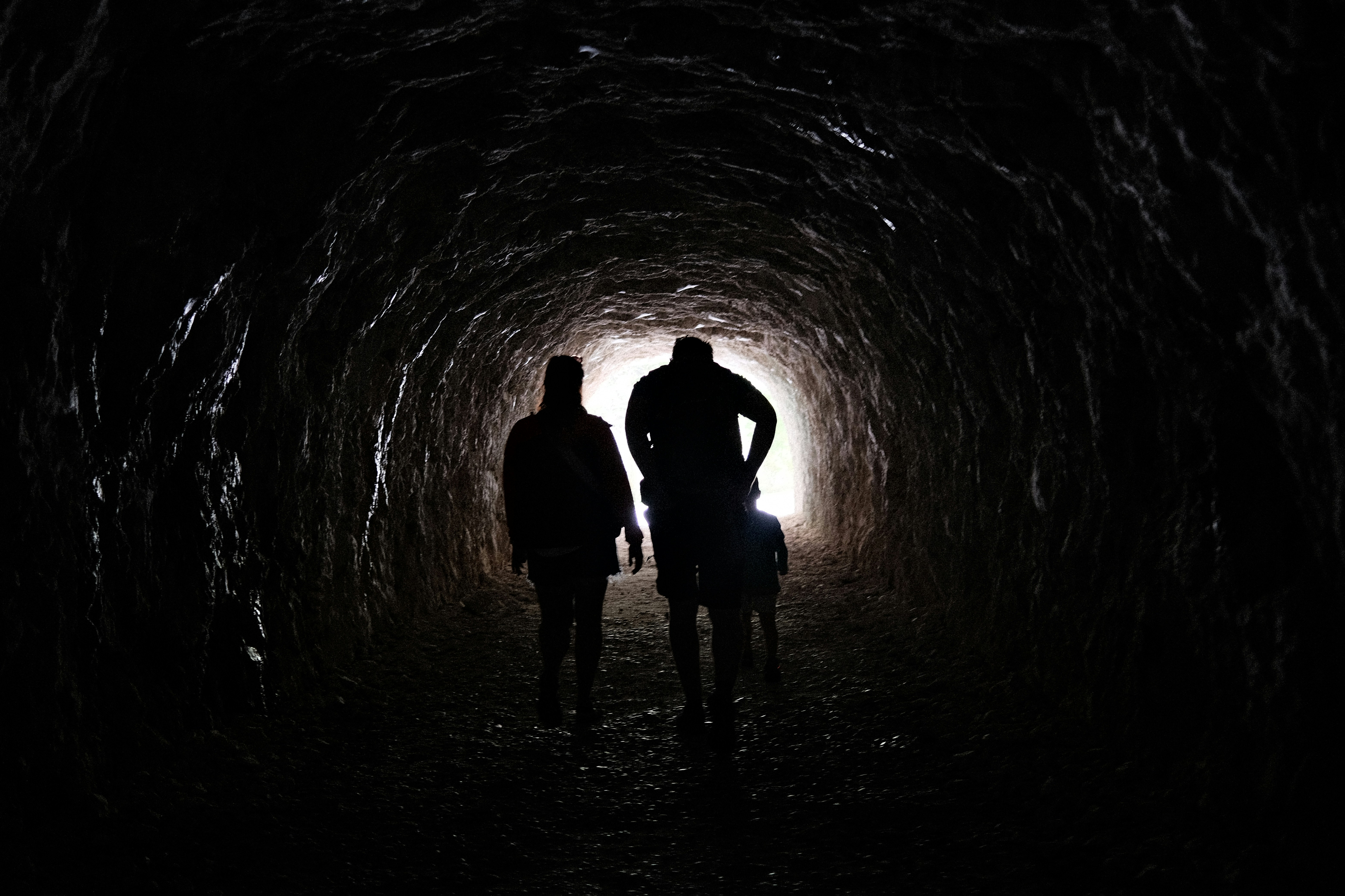 Two figures walk through a dark cave tunnel. photo – Free People Image ...