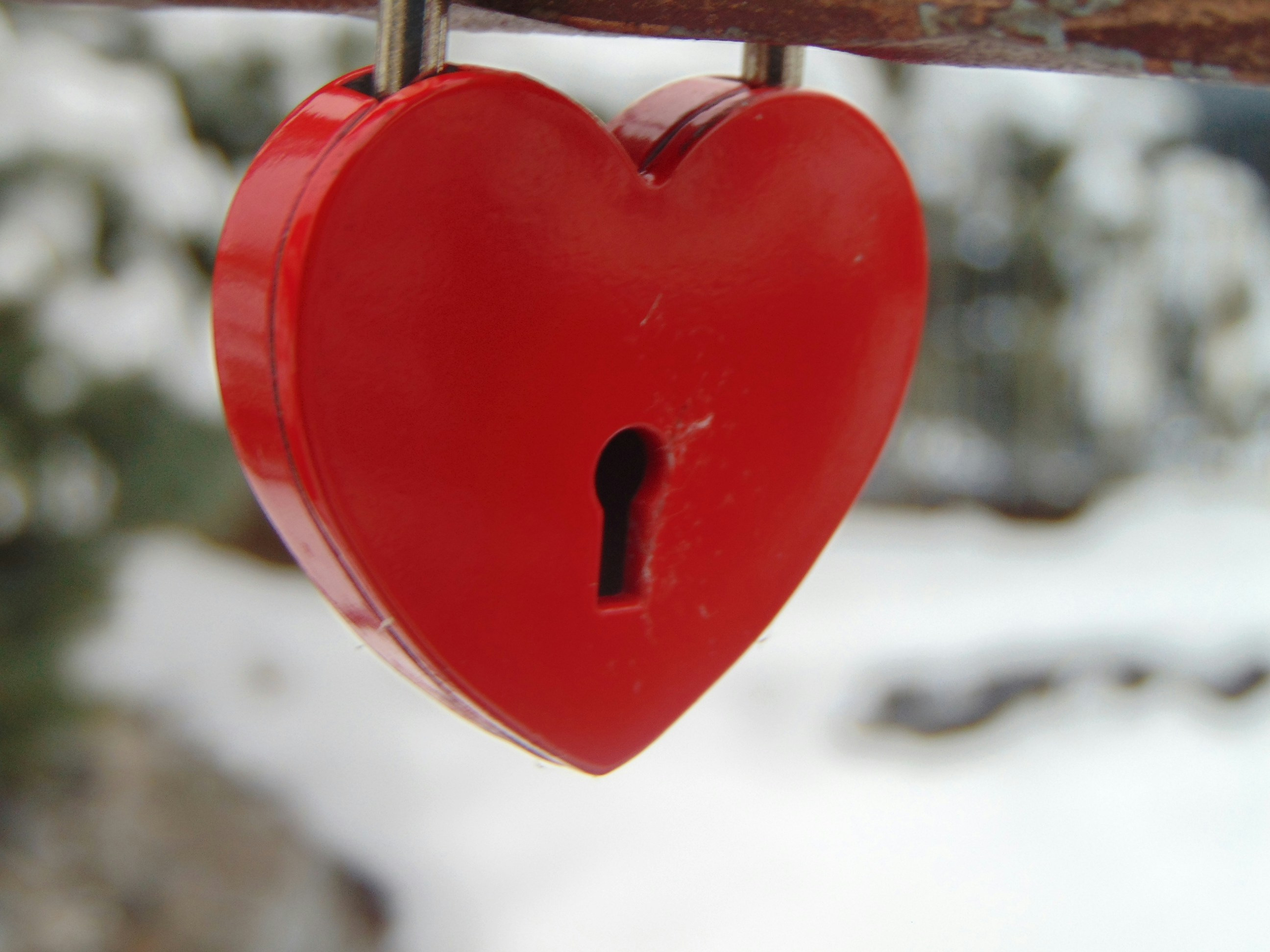 A red heart-shaped padlock hangs outdoors.