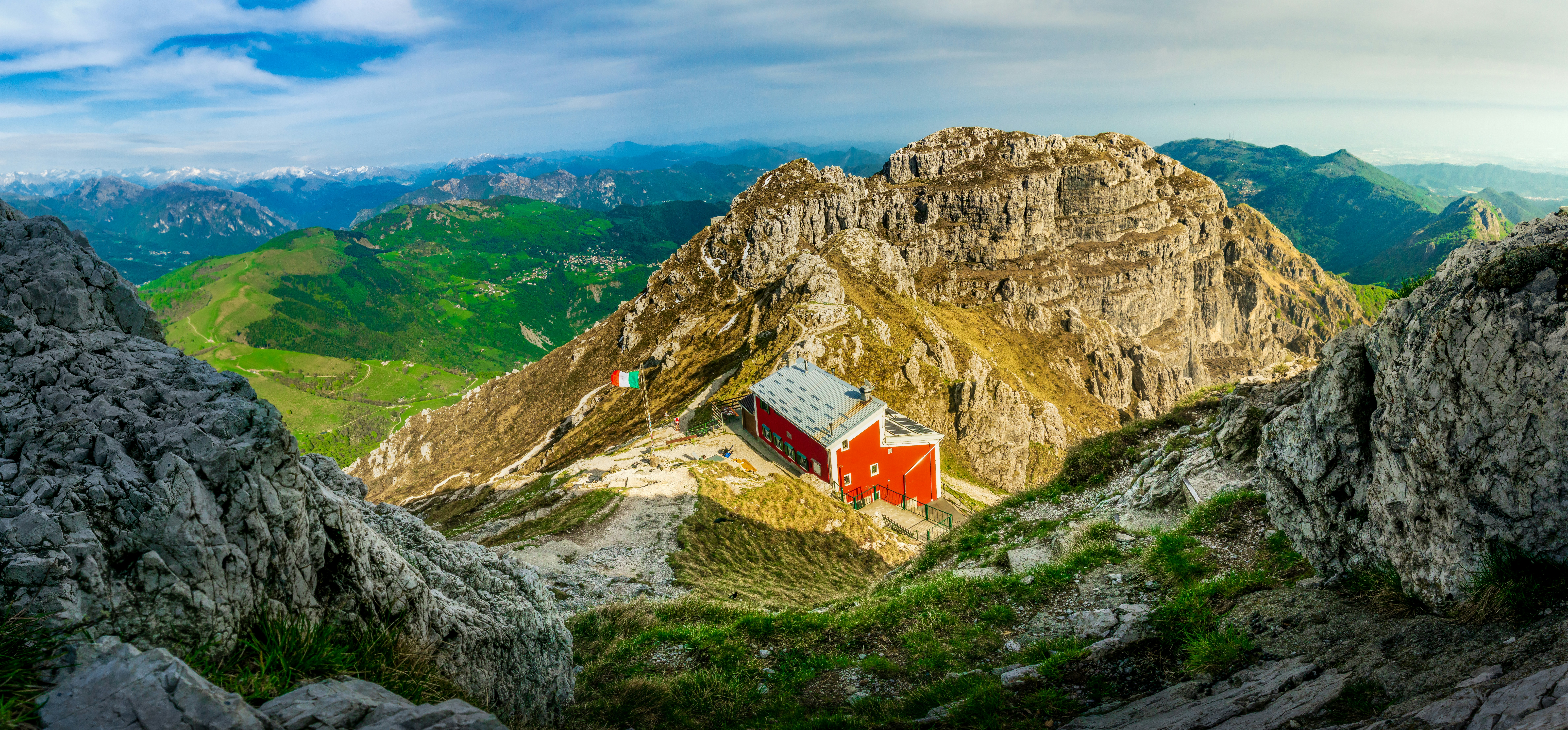 Red cabin on a granite ridge under a blue Alpine sky