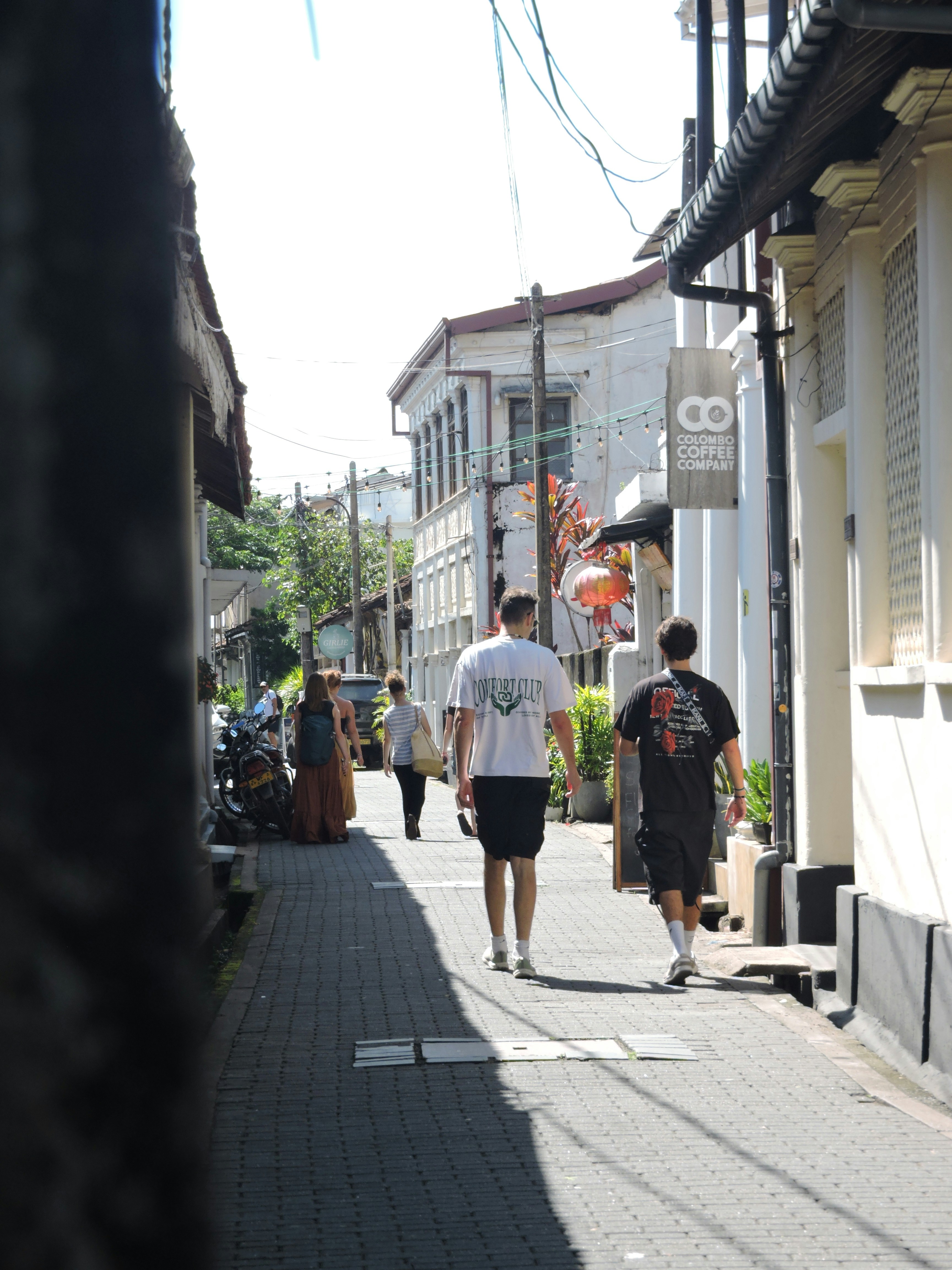 People walking down a narrow cobblestone street.