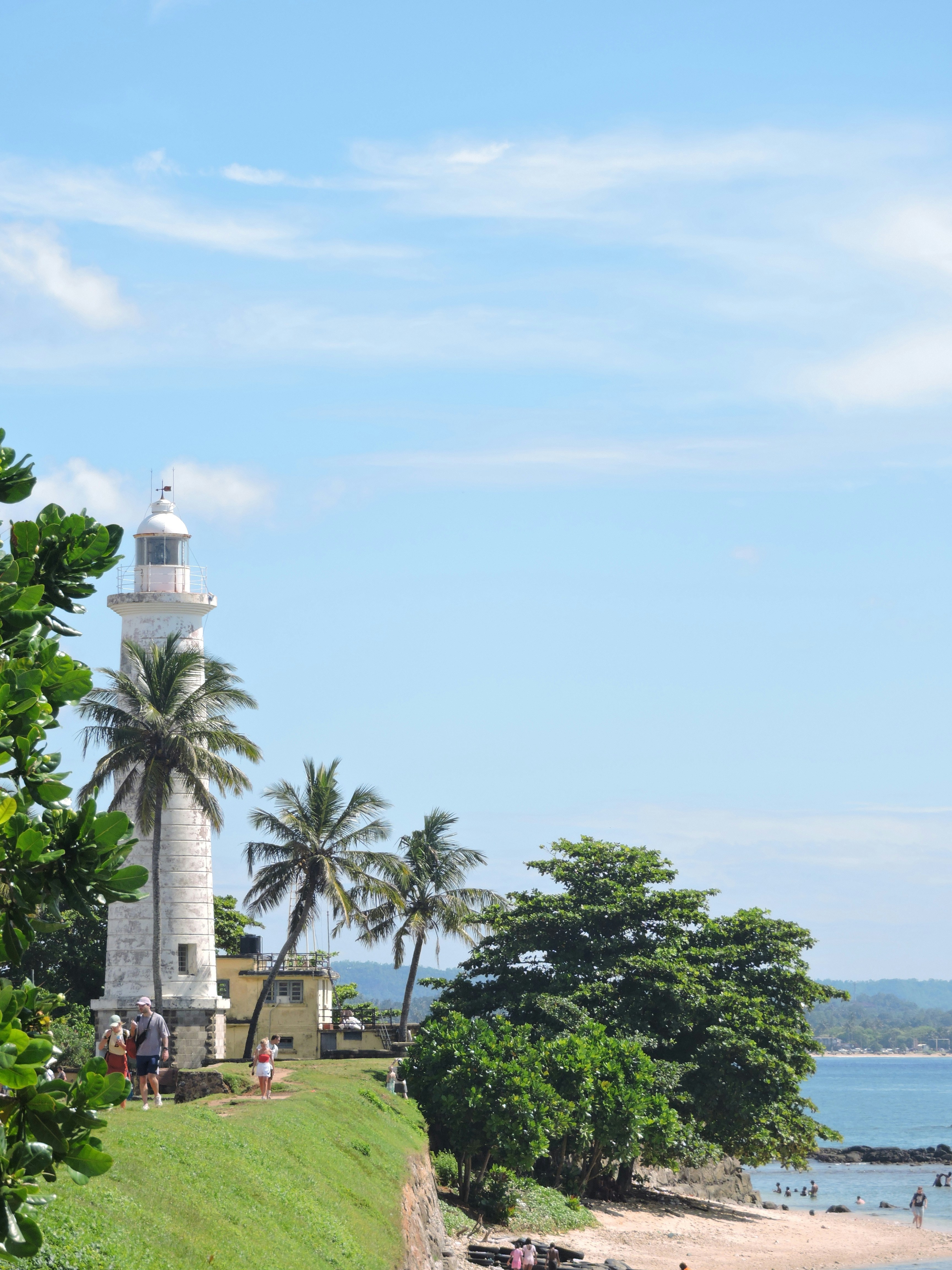 White lighthouse on a grassy cliff overlooking the ocean.