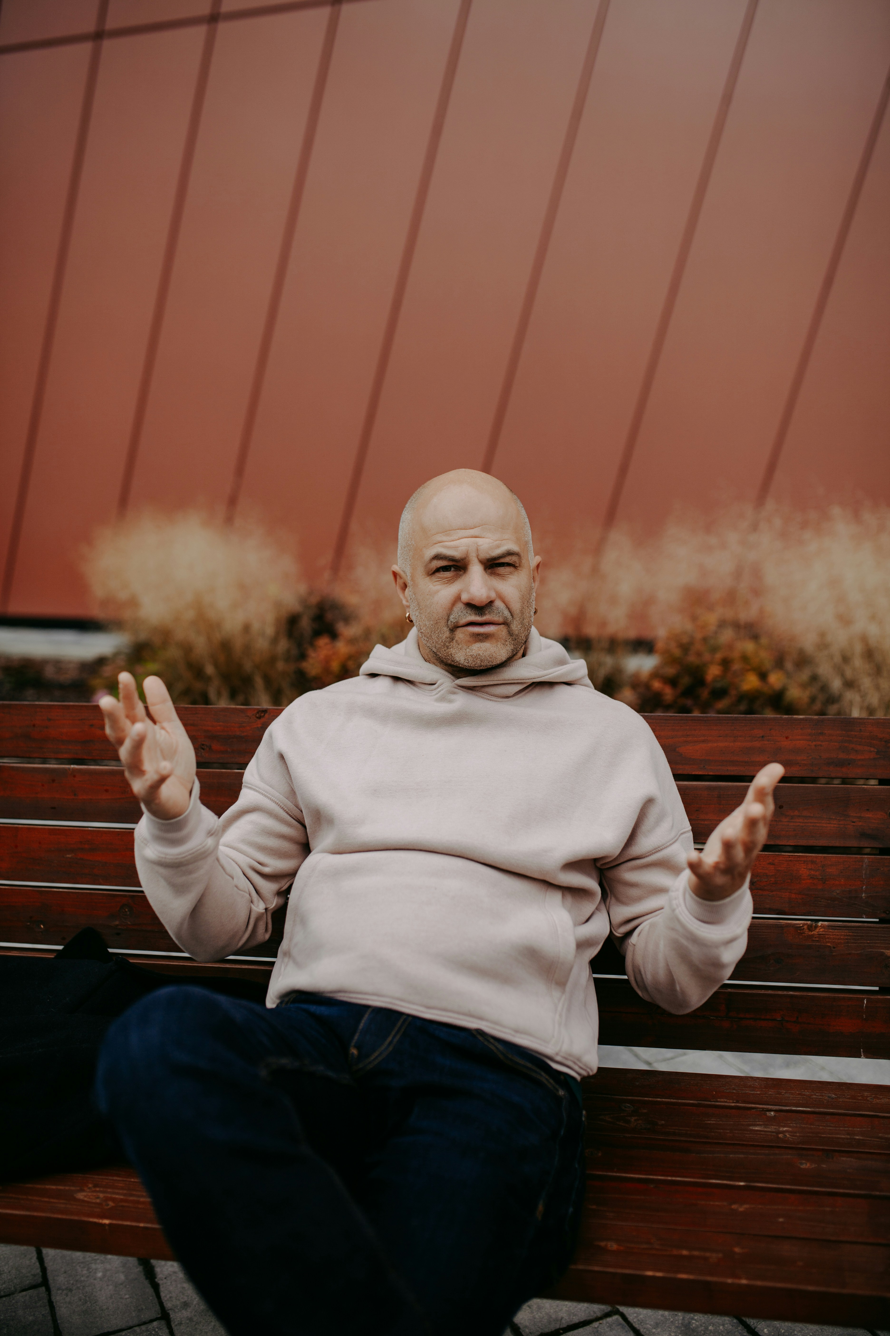 Bald man in hoodie sitting on a bench. photo – Free Portrait Image on ...