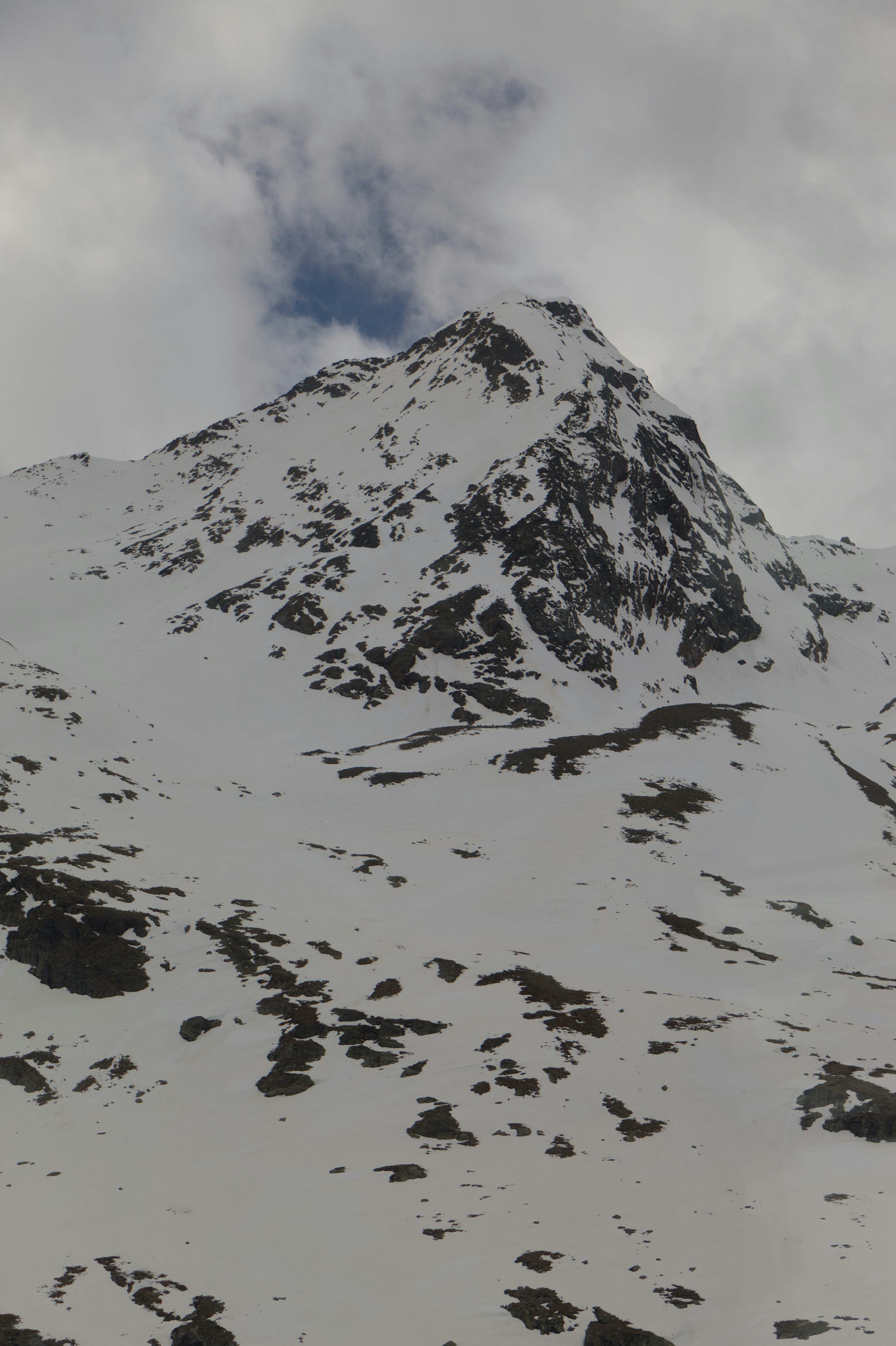 Snowbound Summit: A Jagged Peak Piercing a Clouded Sky