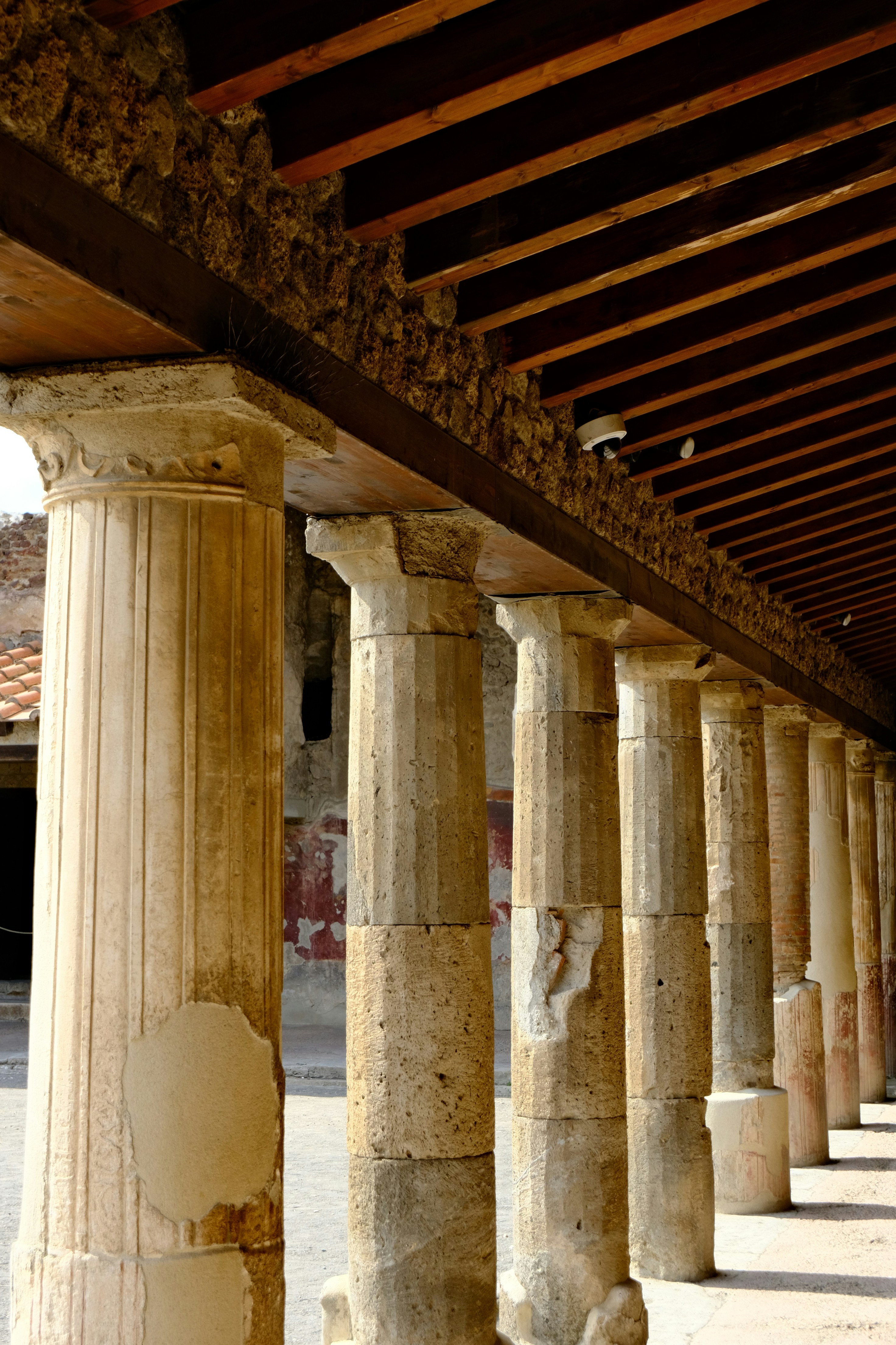 Colonnade of Time: Weathered Stones Under a Wooden Arcade