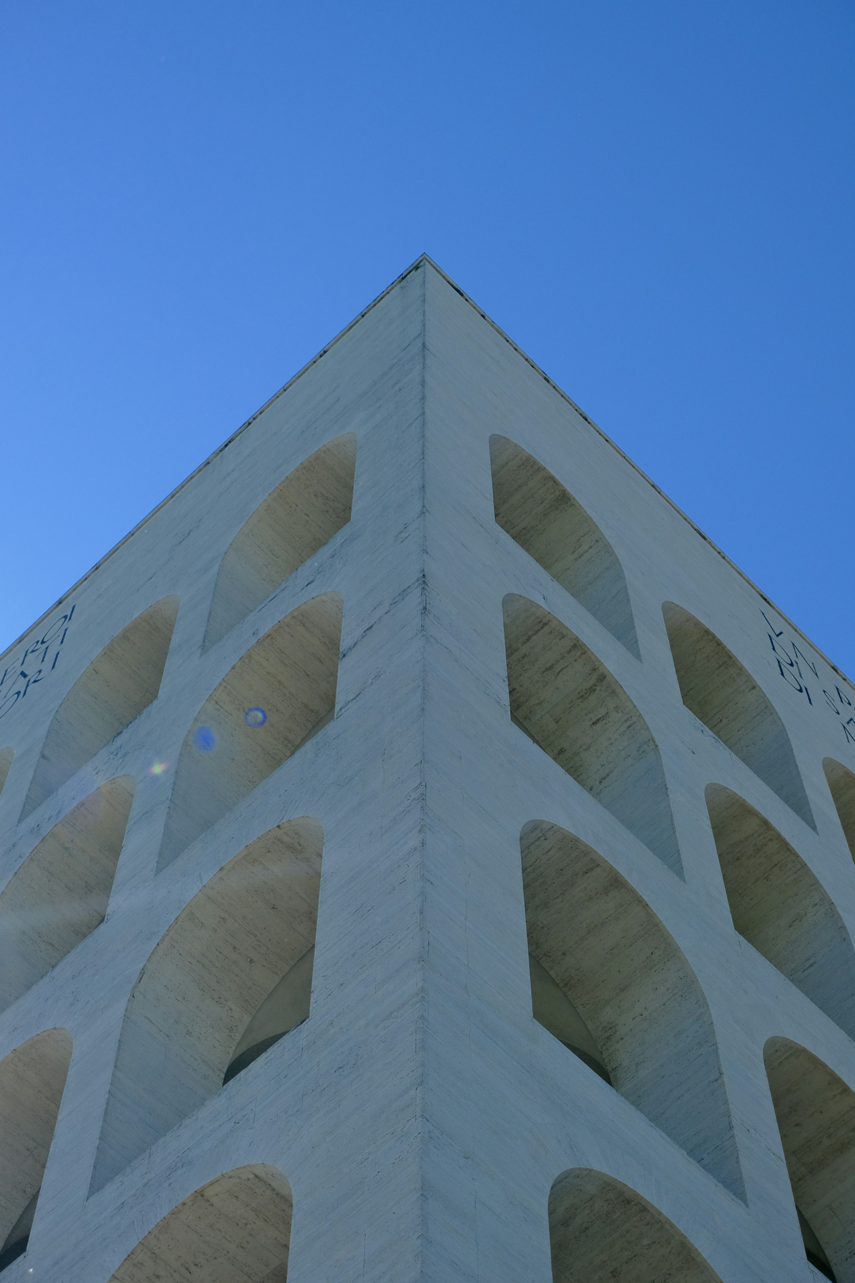 Abstract Corner: Light-washed Archway Facade Against a Clear Blue Sky