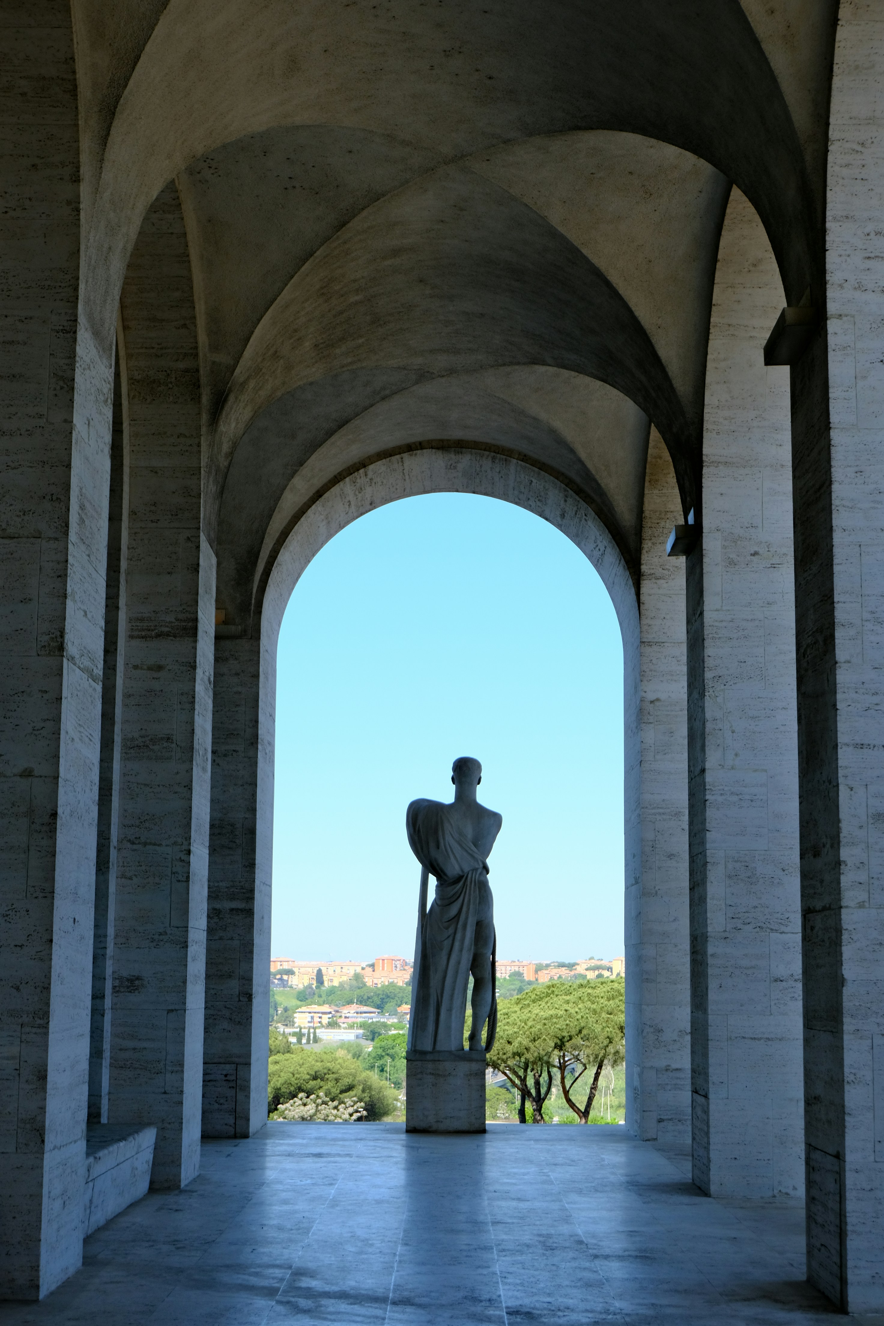 Arcade of Echoes: The Statue Framed by Dawn-lit Vaults