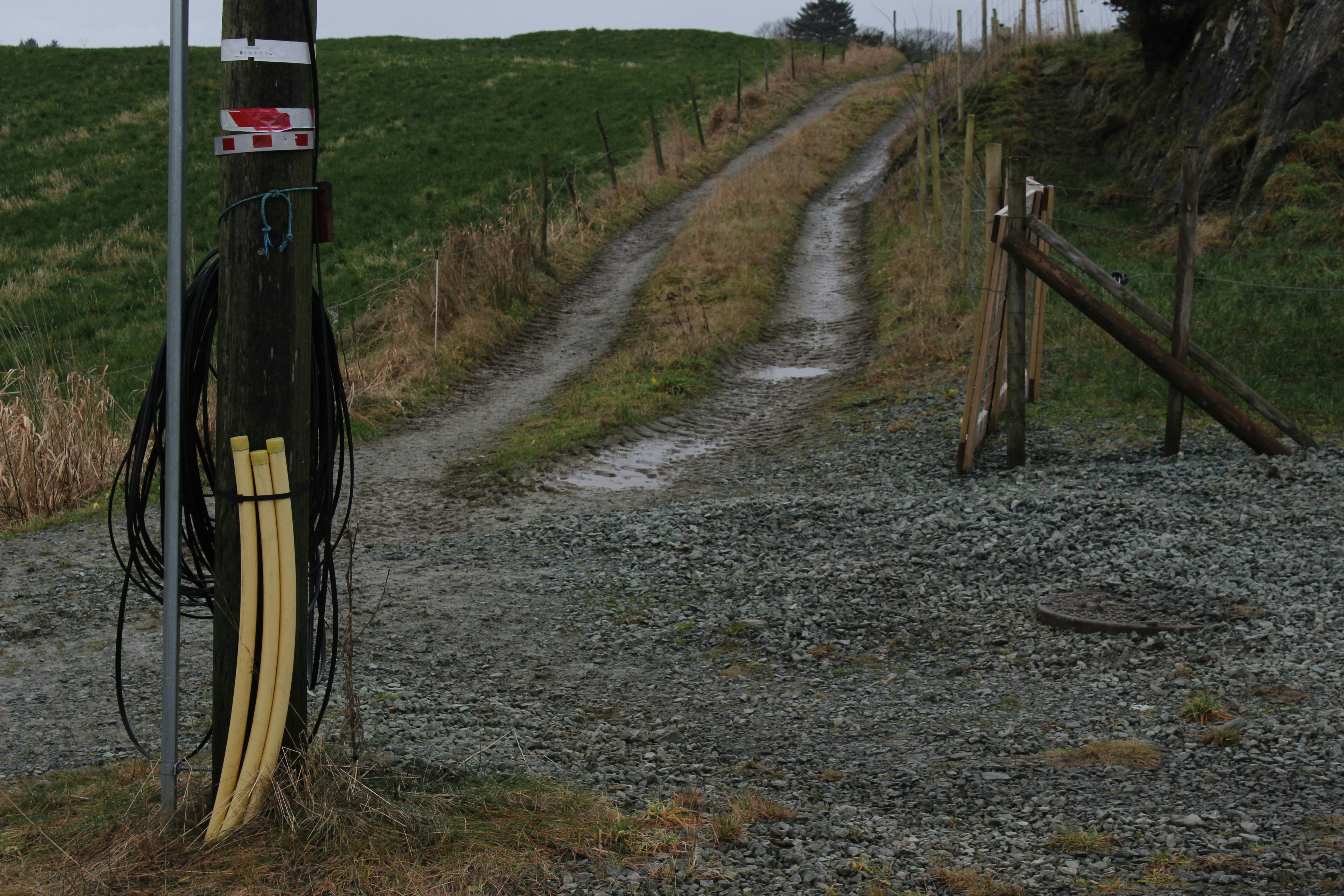 Rugged Dirt Road Ascending Through a Weathered Utility Scene