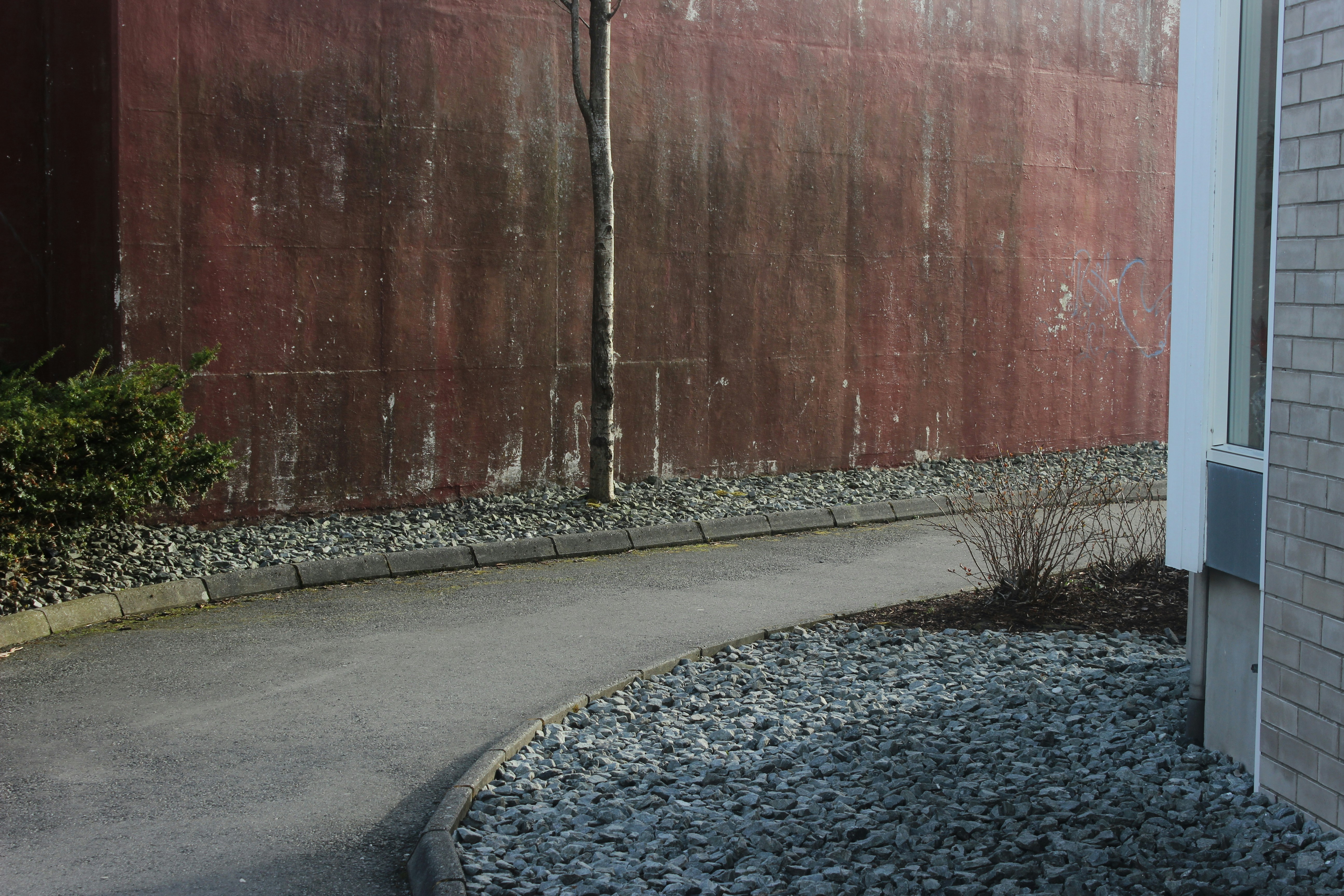 Concrete Road Curvature Meets Red Privacy Wall