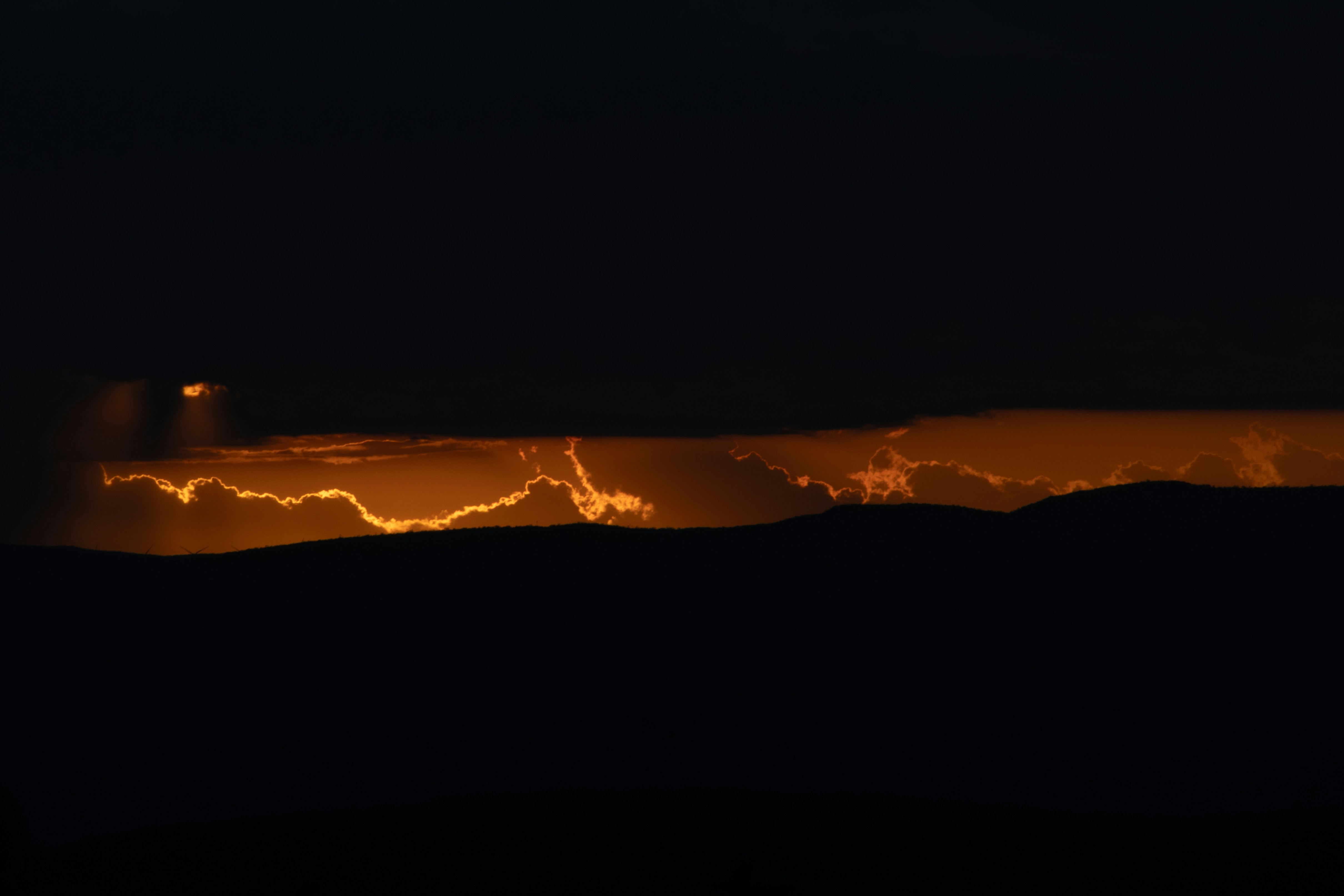 Fiery horizon: molten veins of dusk over silhouetted ridges
