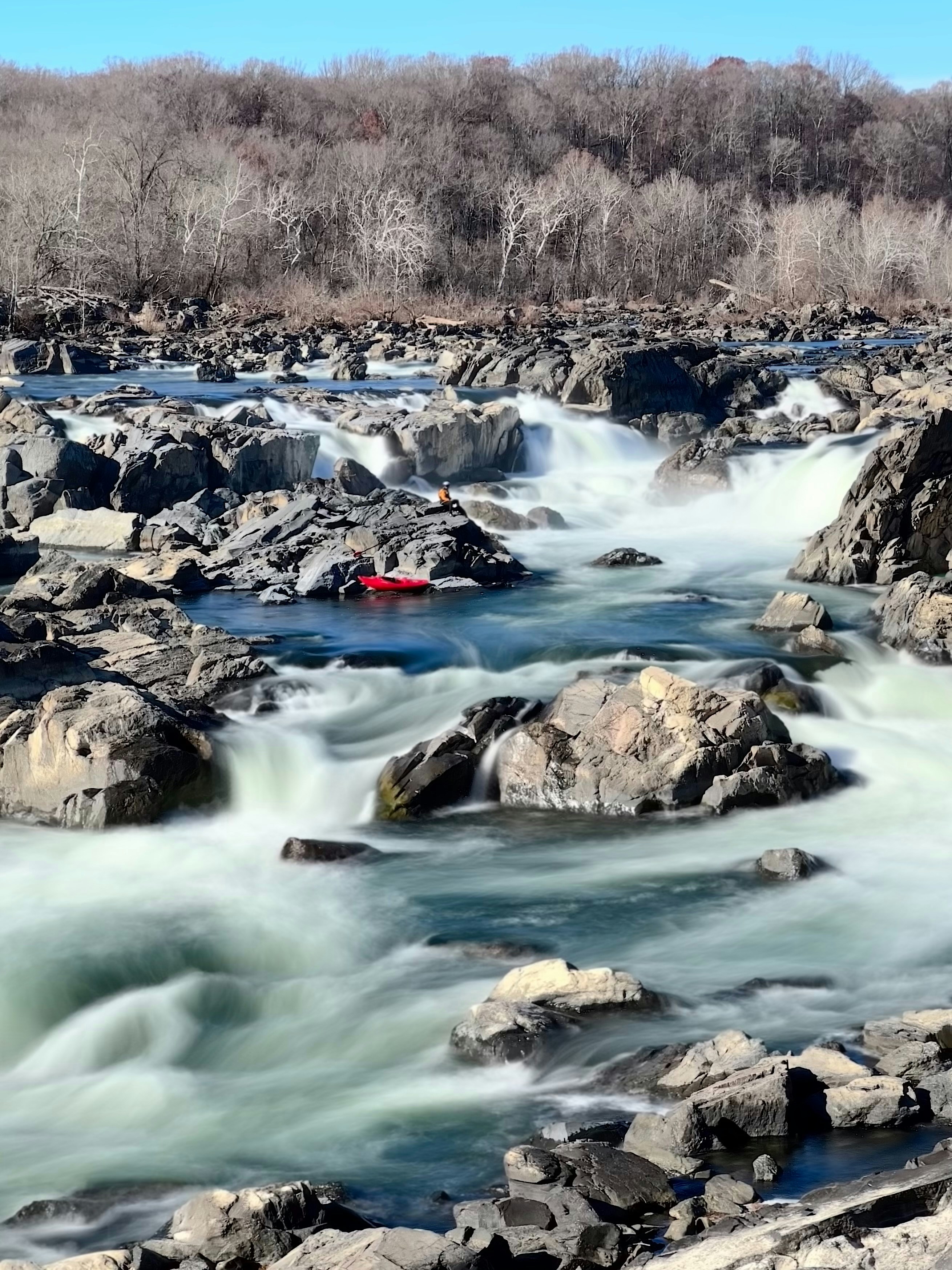 Rushing river through rugged volcanic rocks under a barren shoreline
