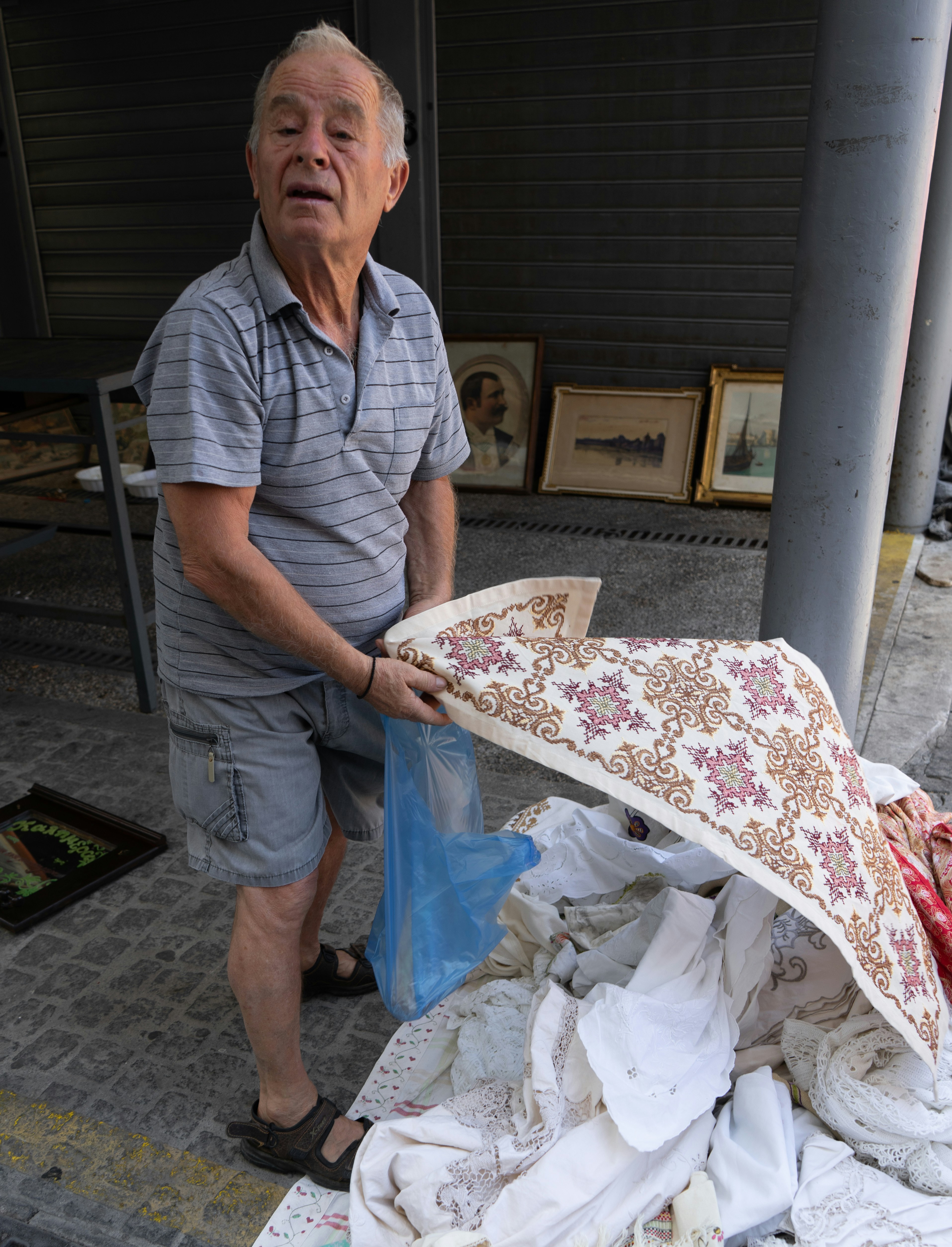 Neatly Draped Fabrics and Framed Keepsakes at a Footpath Stall