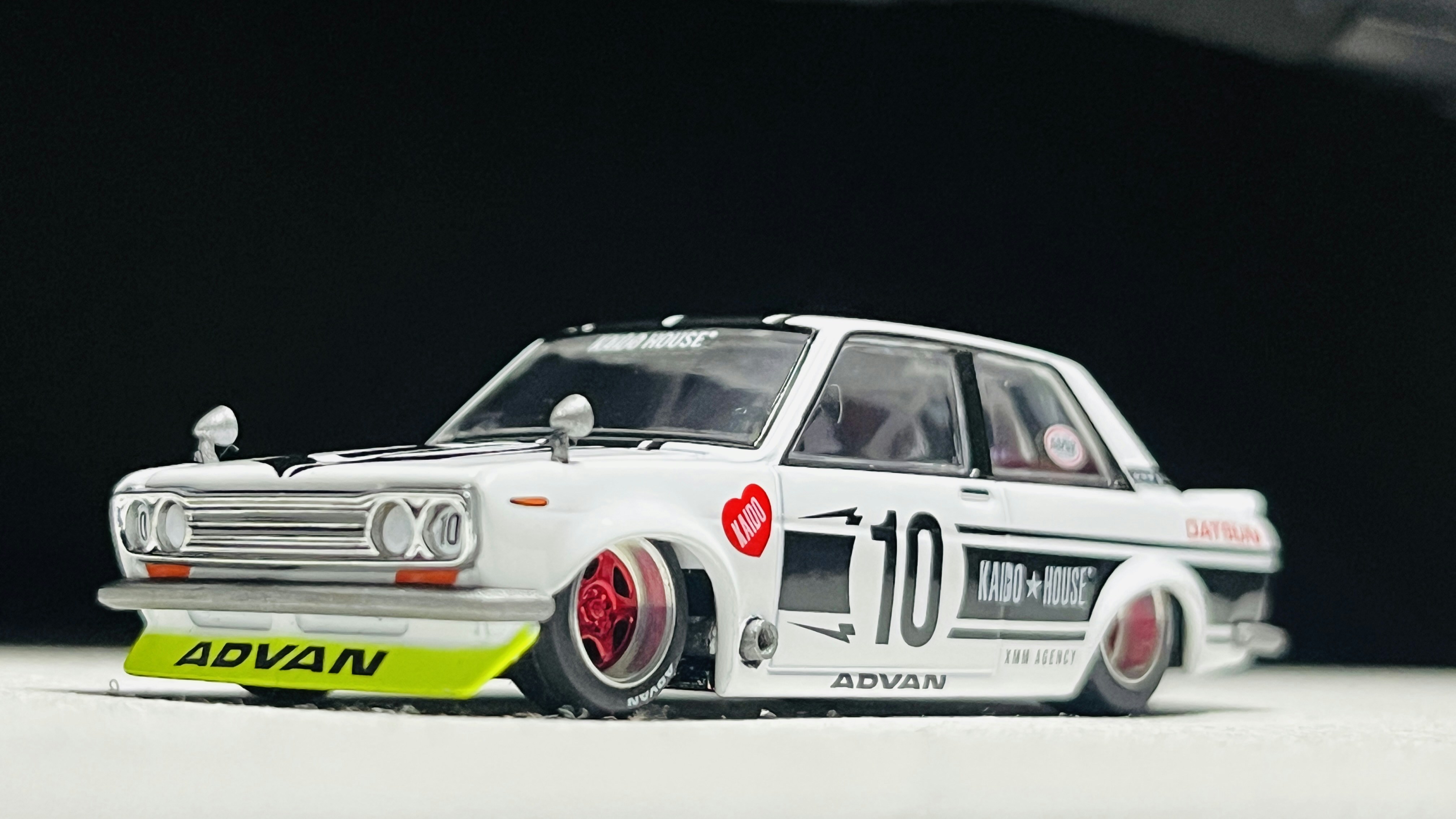 Miniature Drift Champion: White rally sedan with red wheels on a bright track