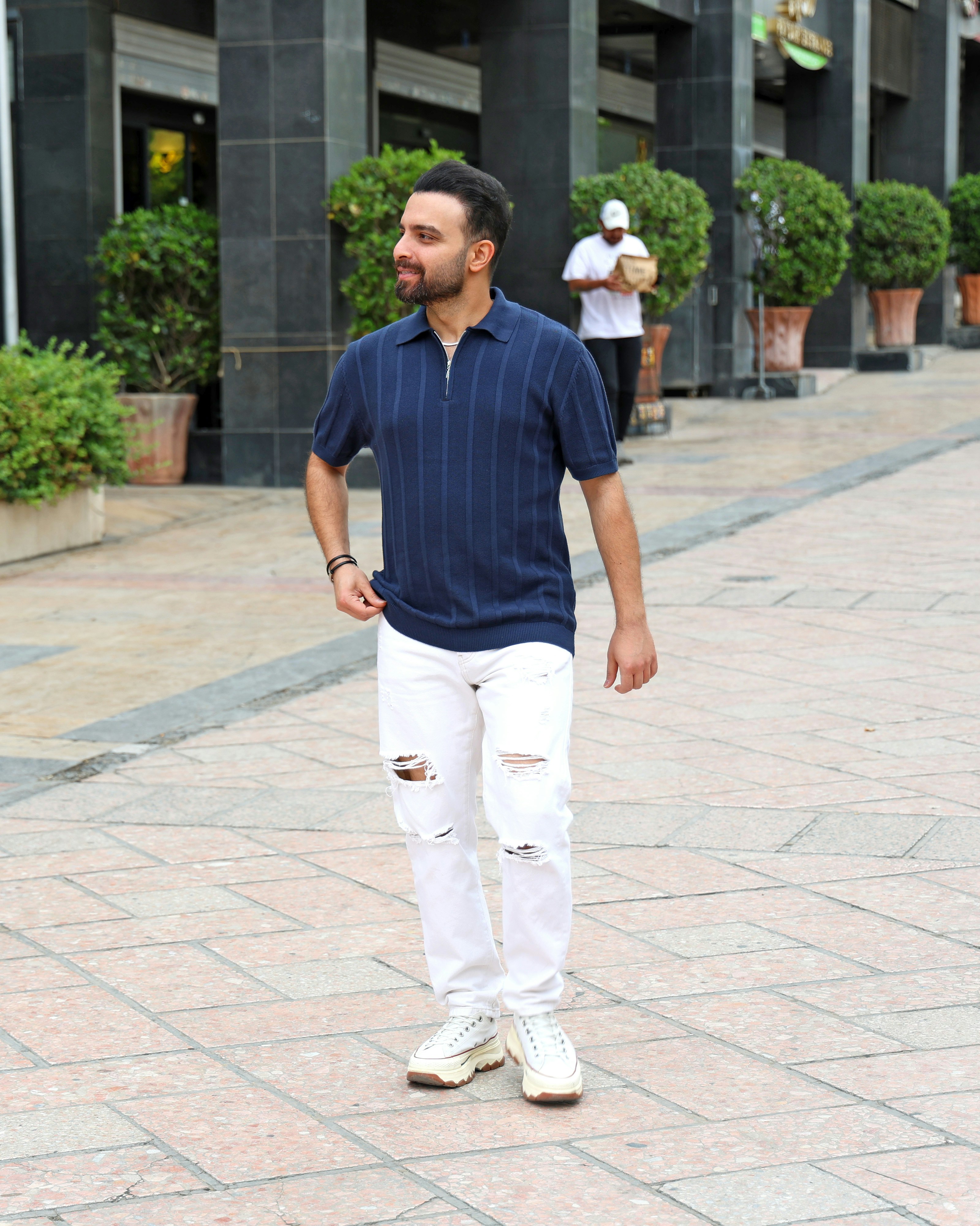 Man in Navy Polo Walking Past a Modern Plaza