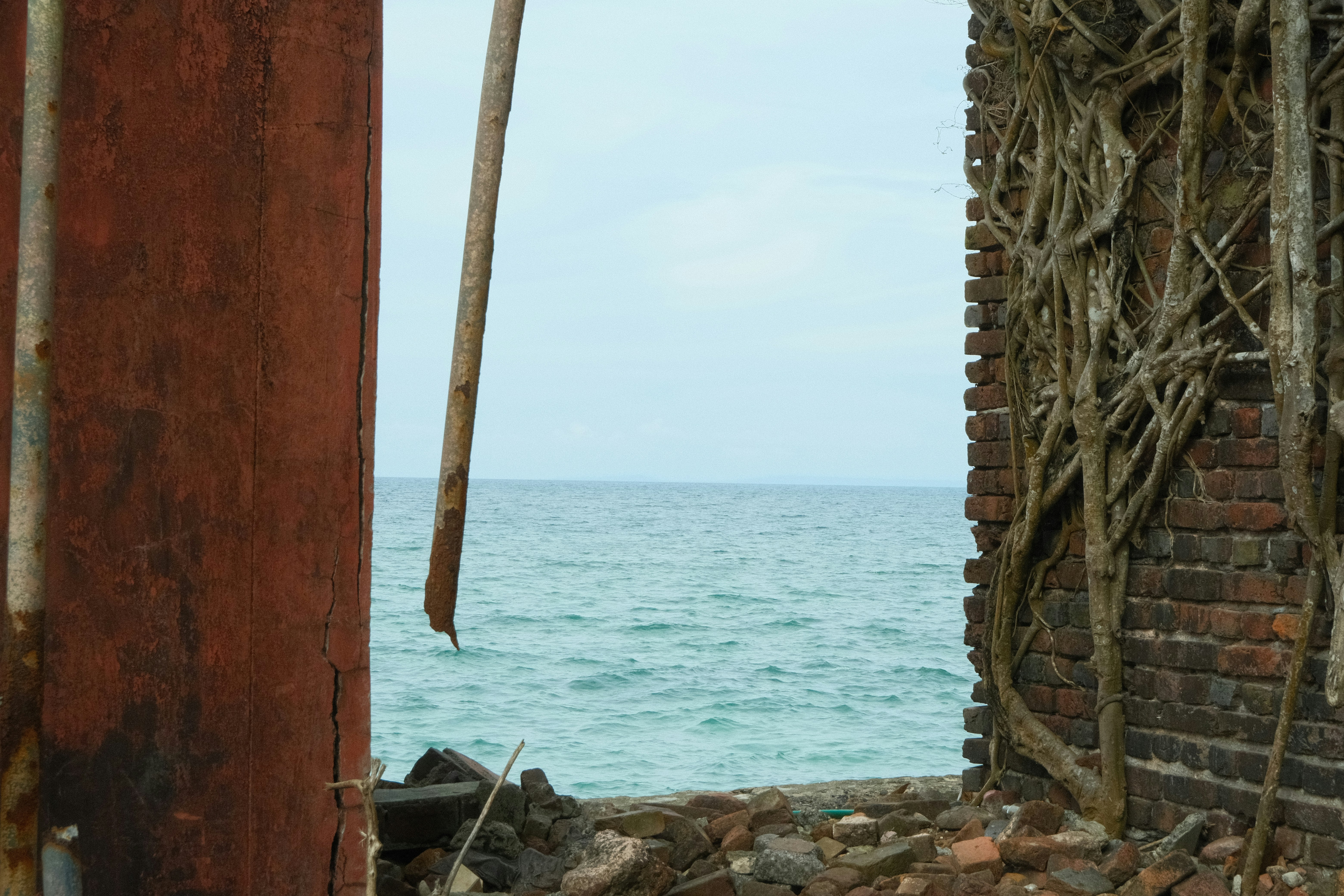 Between Rubble and Sea: A Fractured Wall Framing a Distant Horizon
