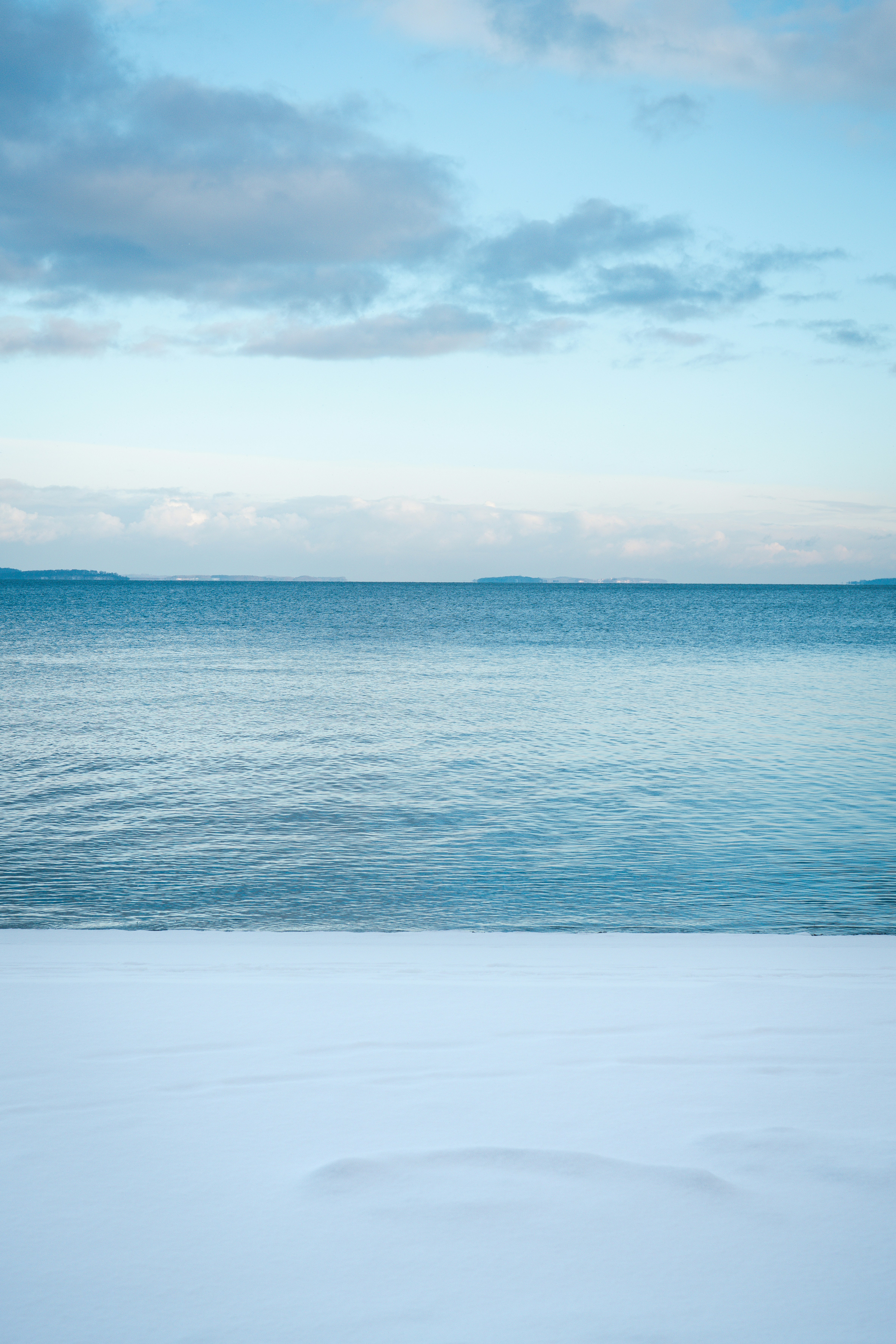 Serene Horizon: Snowy Beach Meets Quiet Ocean