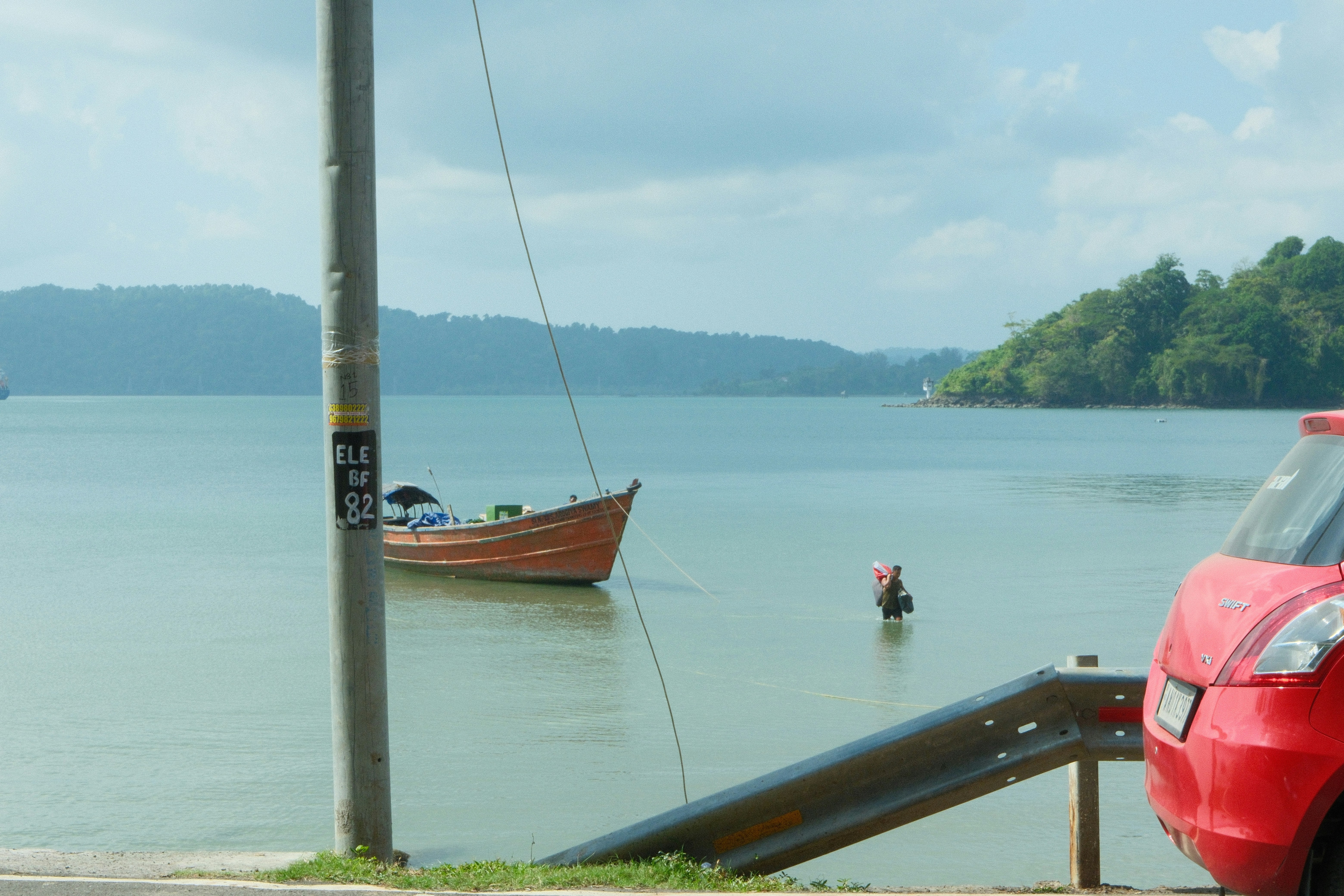 Red Ship, Calm Water, and a Roadside Scene by the Bay