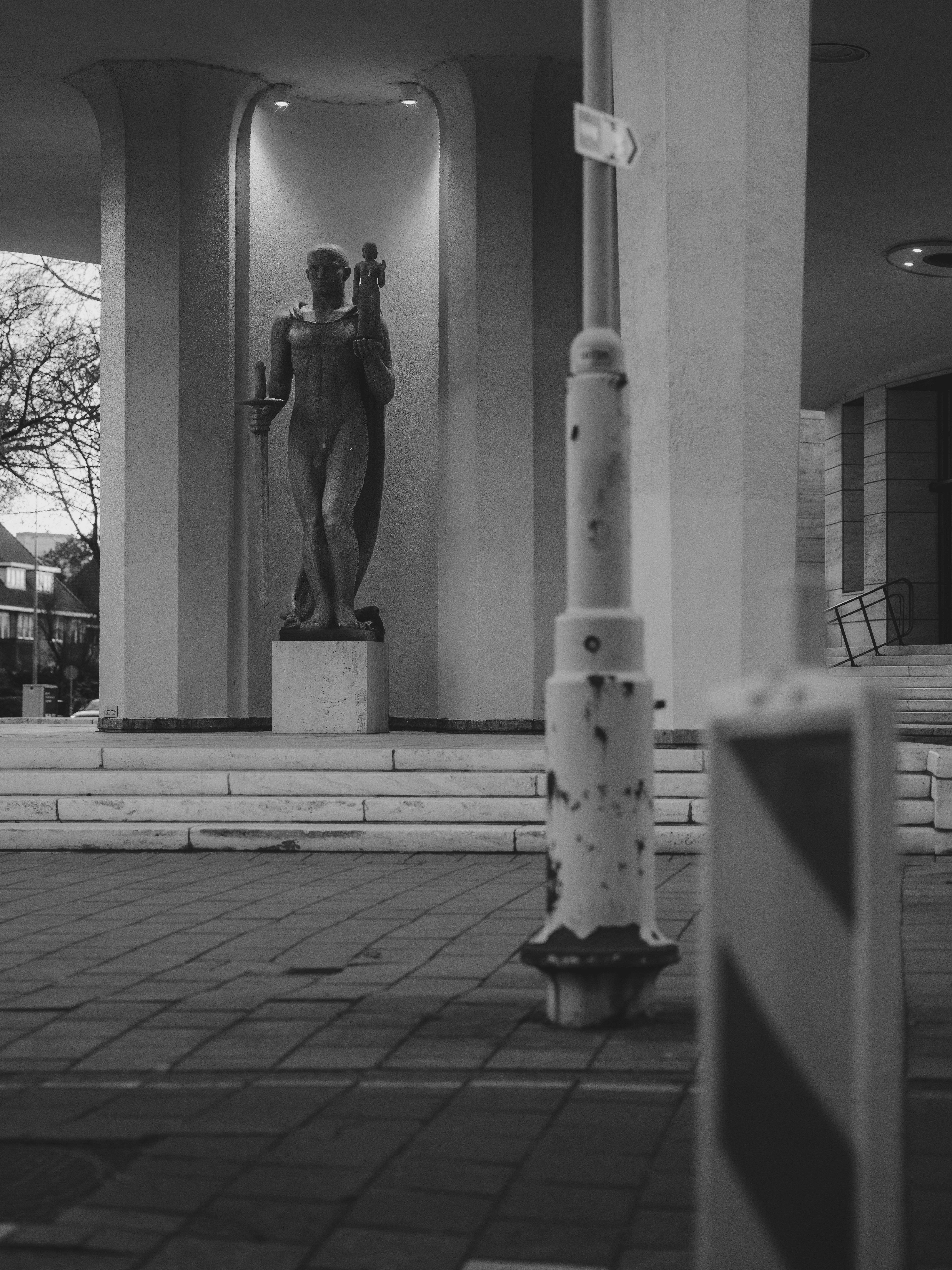 Statue under concrete arches: a quiet urban vignette at the museum steps
