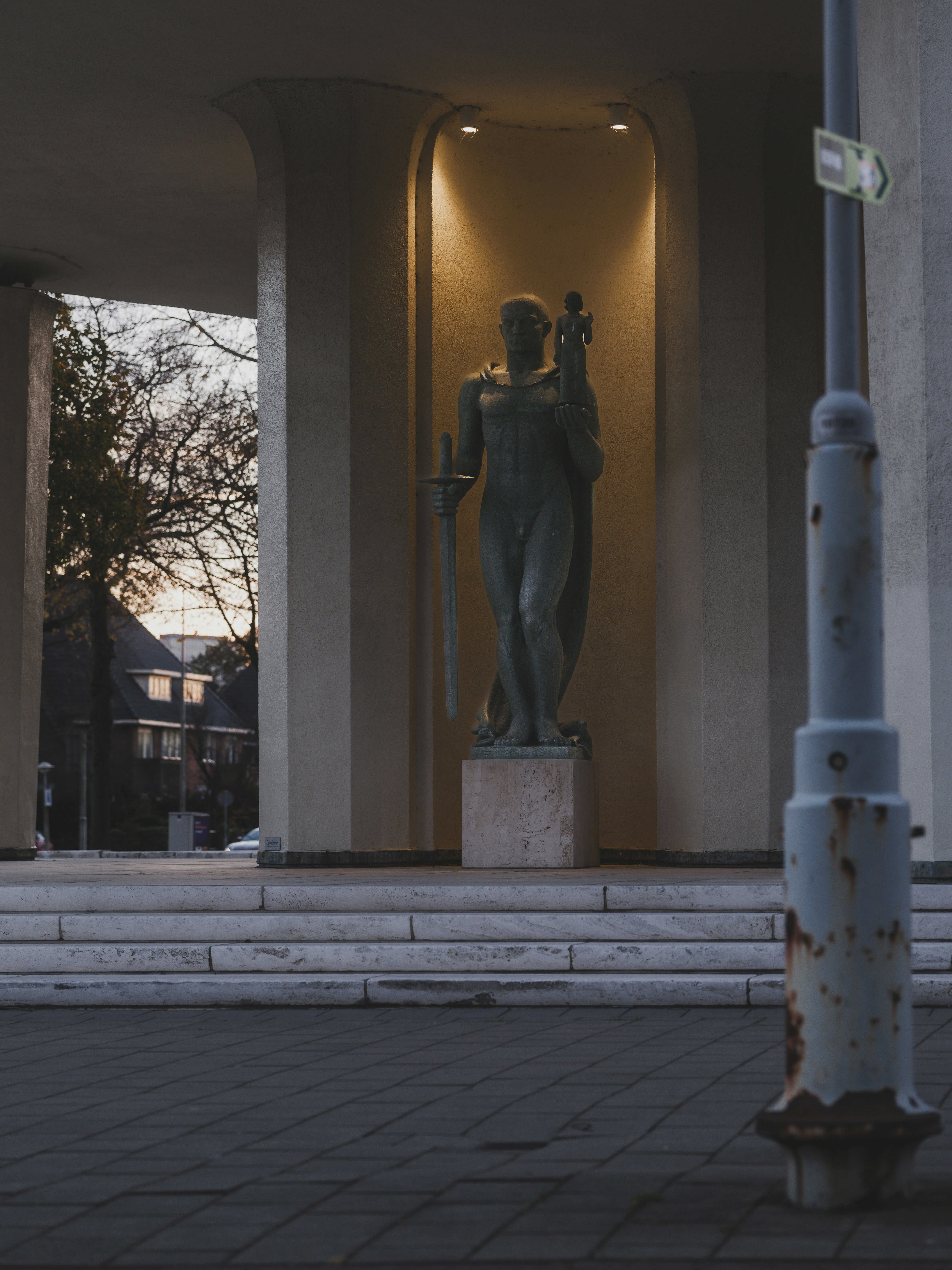 Guardian in the Shadowed Niche: A Bronze Statue Beneath Circles of Light