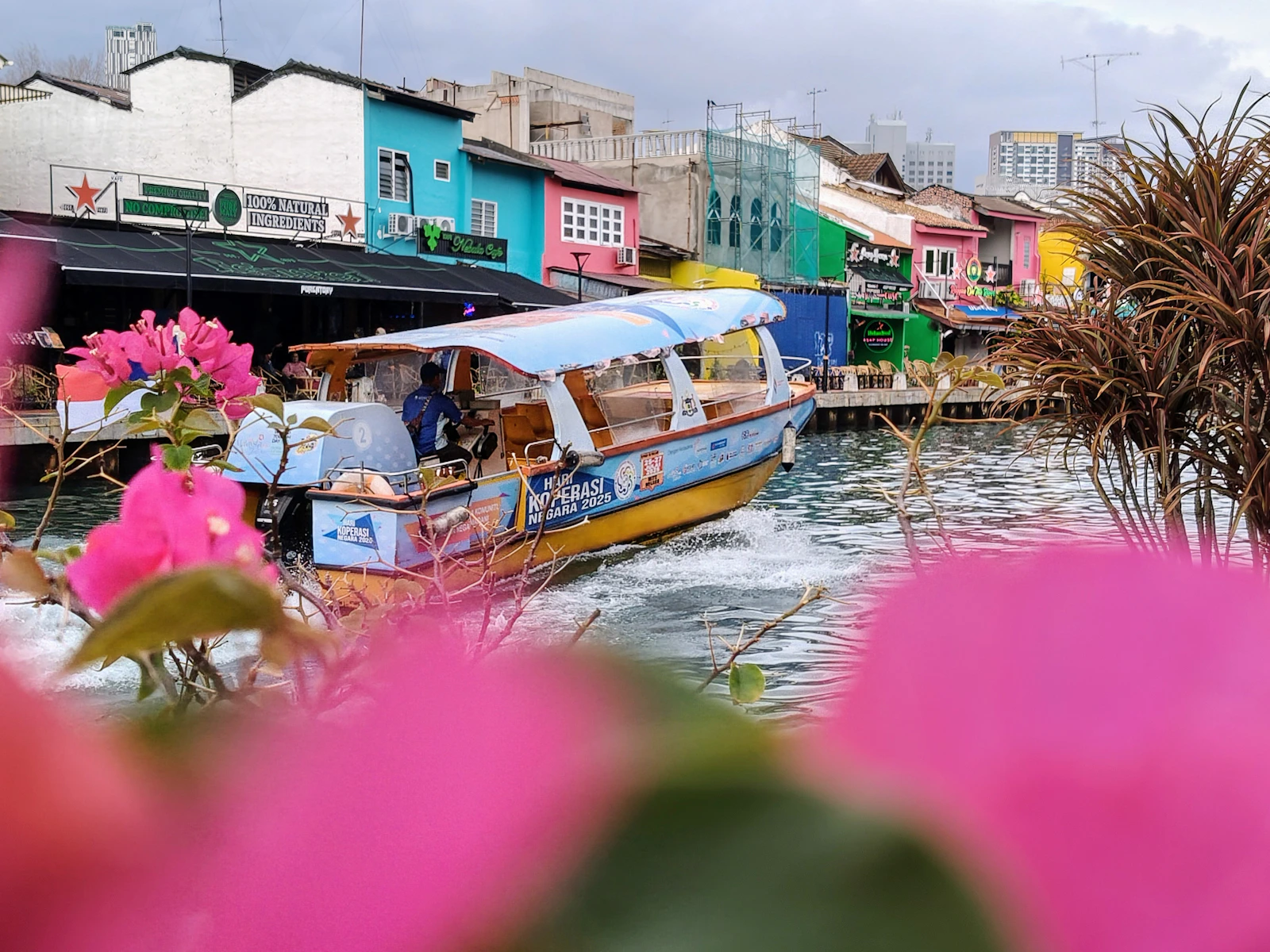 Vibrant canalfront in bloom: a colorful boat glides past painted shanties