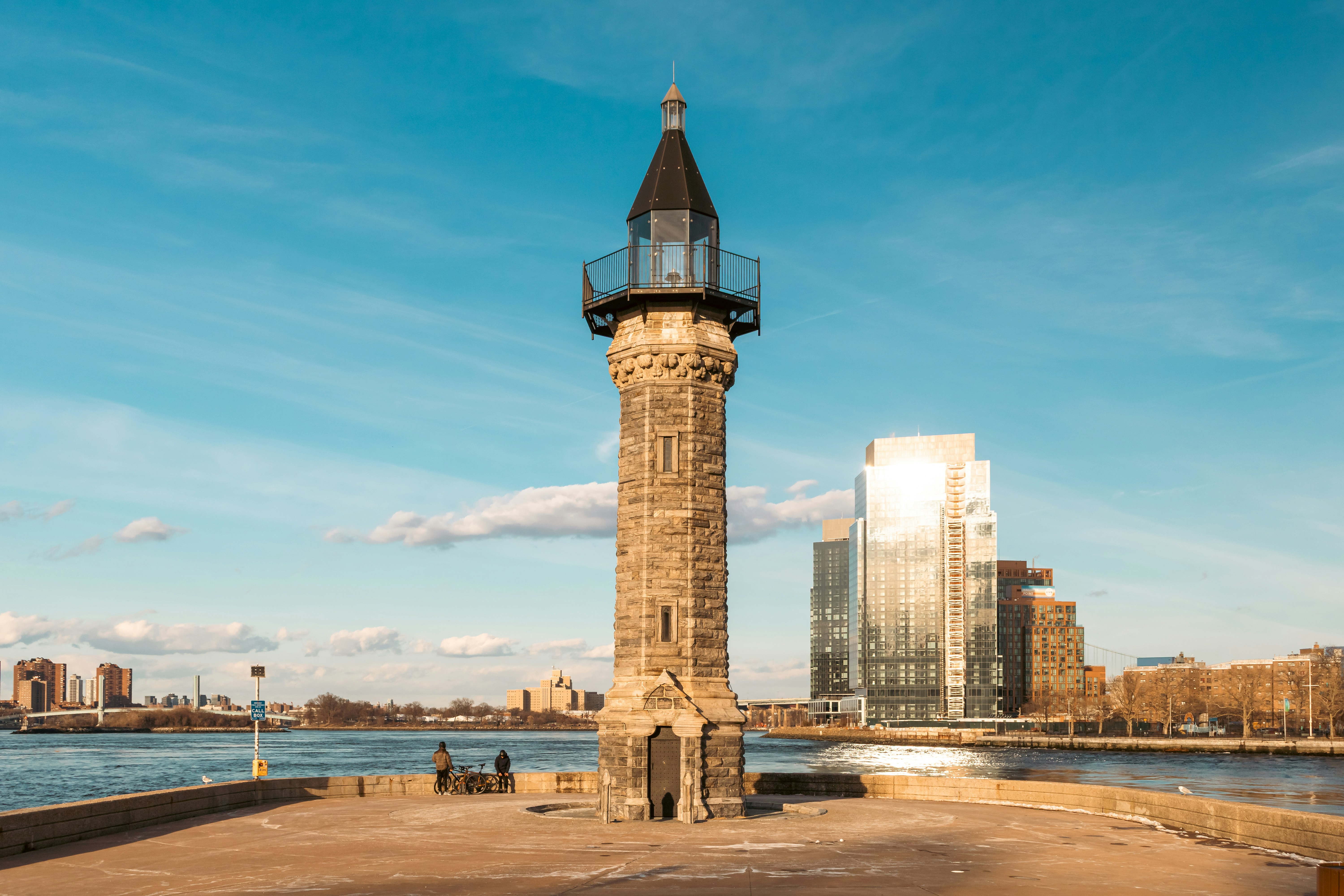 Harbor Beacon: Stone Lighthouse with Modern Skyline