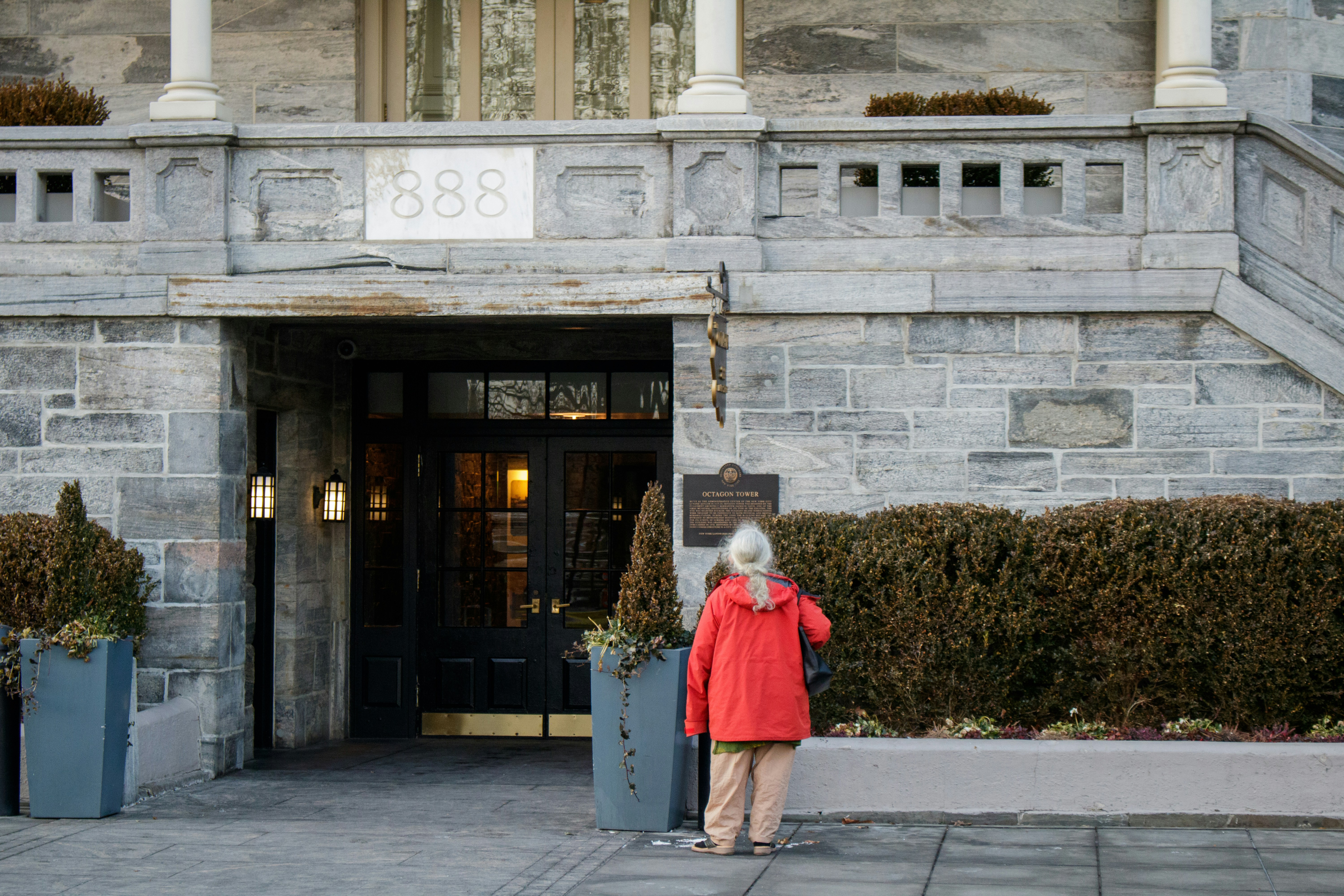 Red-clad visitor at the stone institutional entrance