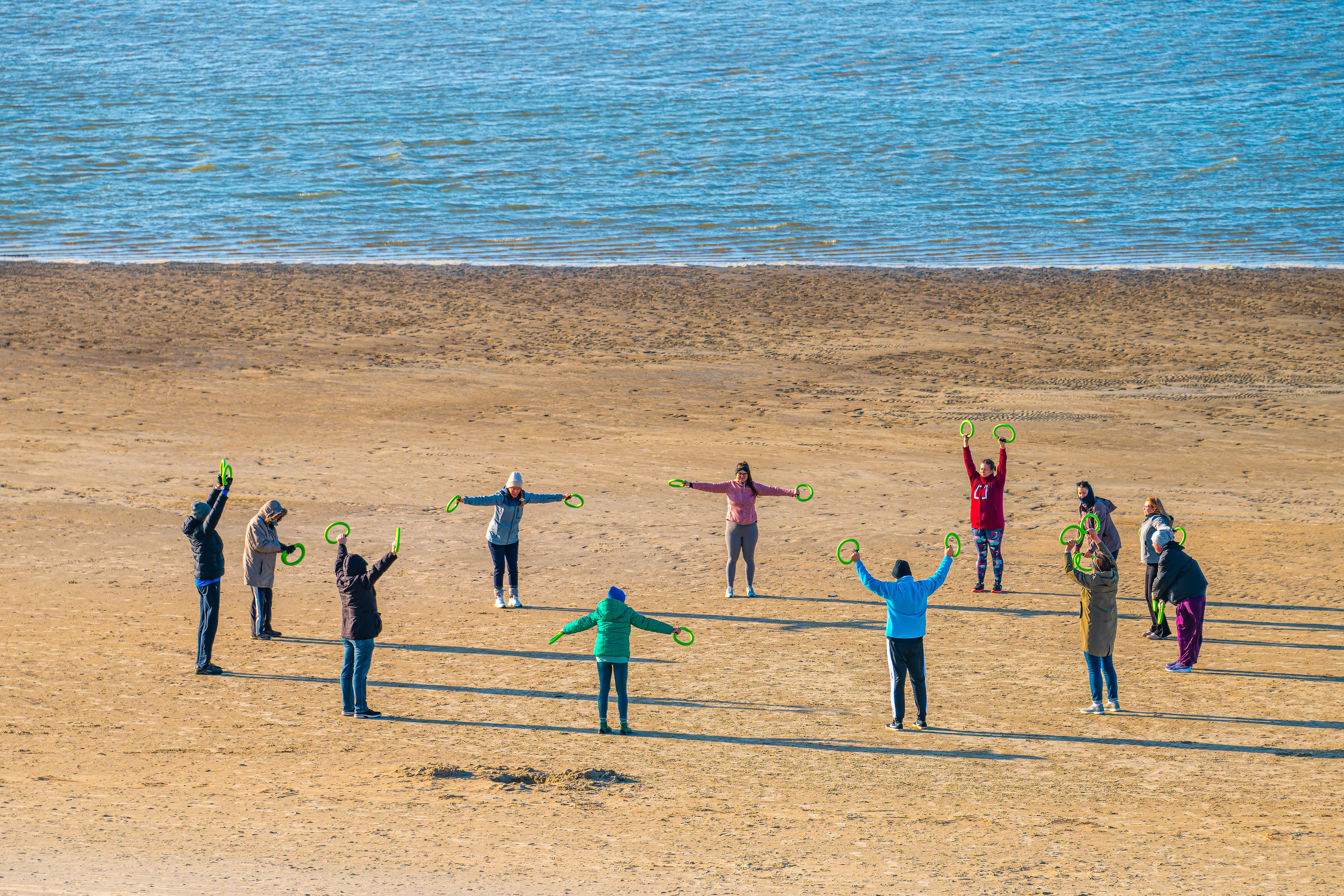 Circle of Balance: Beachgoers in Yoga-like Pose with Boards